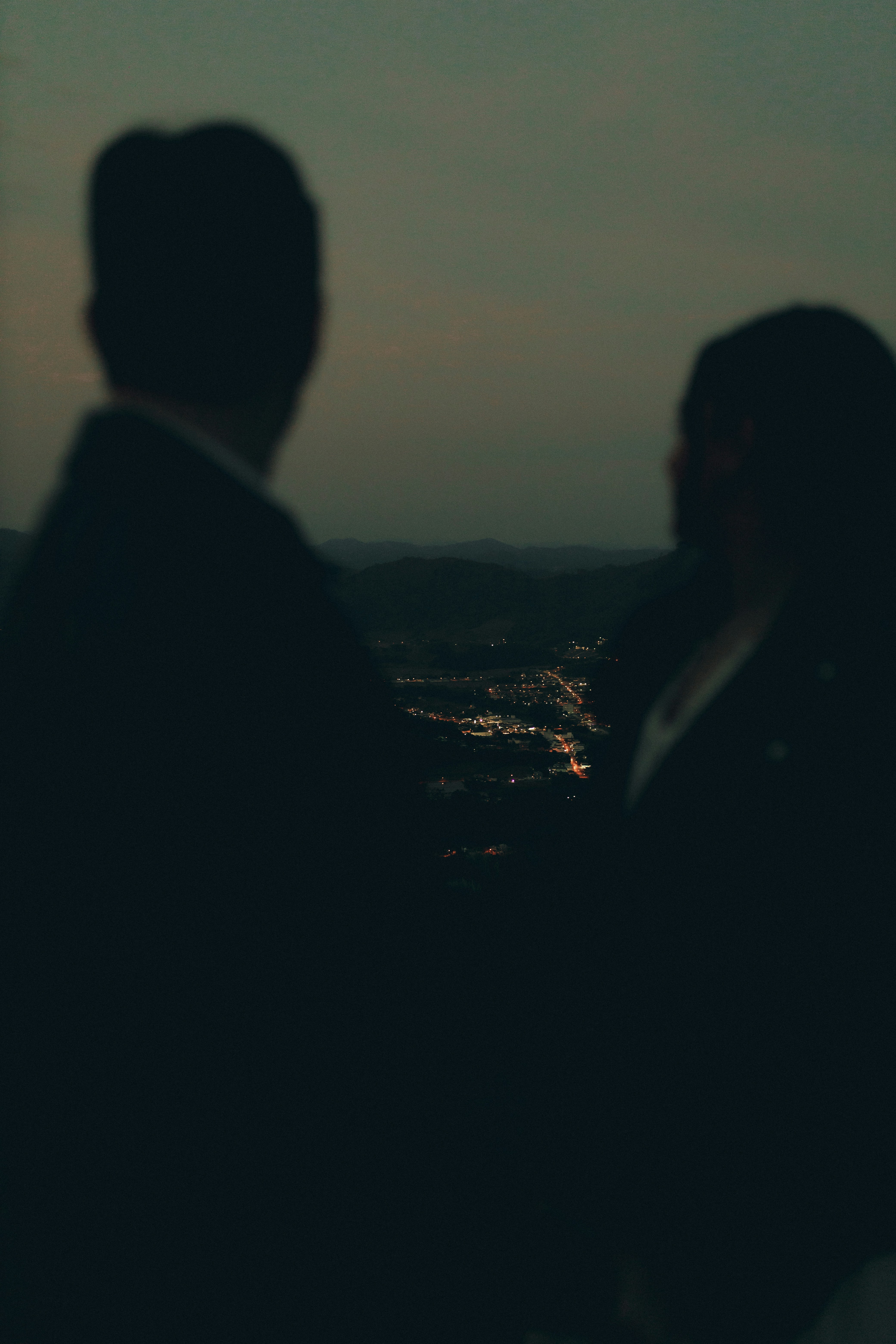 Couple silhouetted against a city view at dusk.