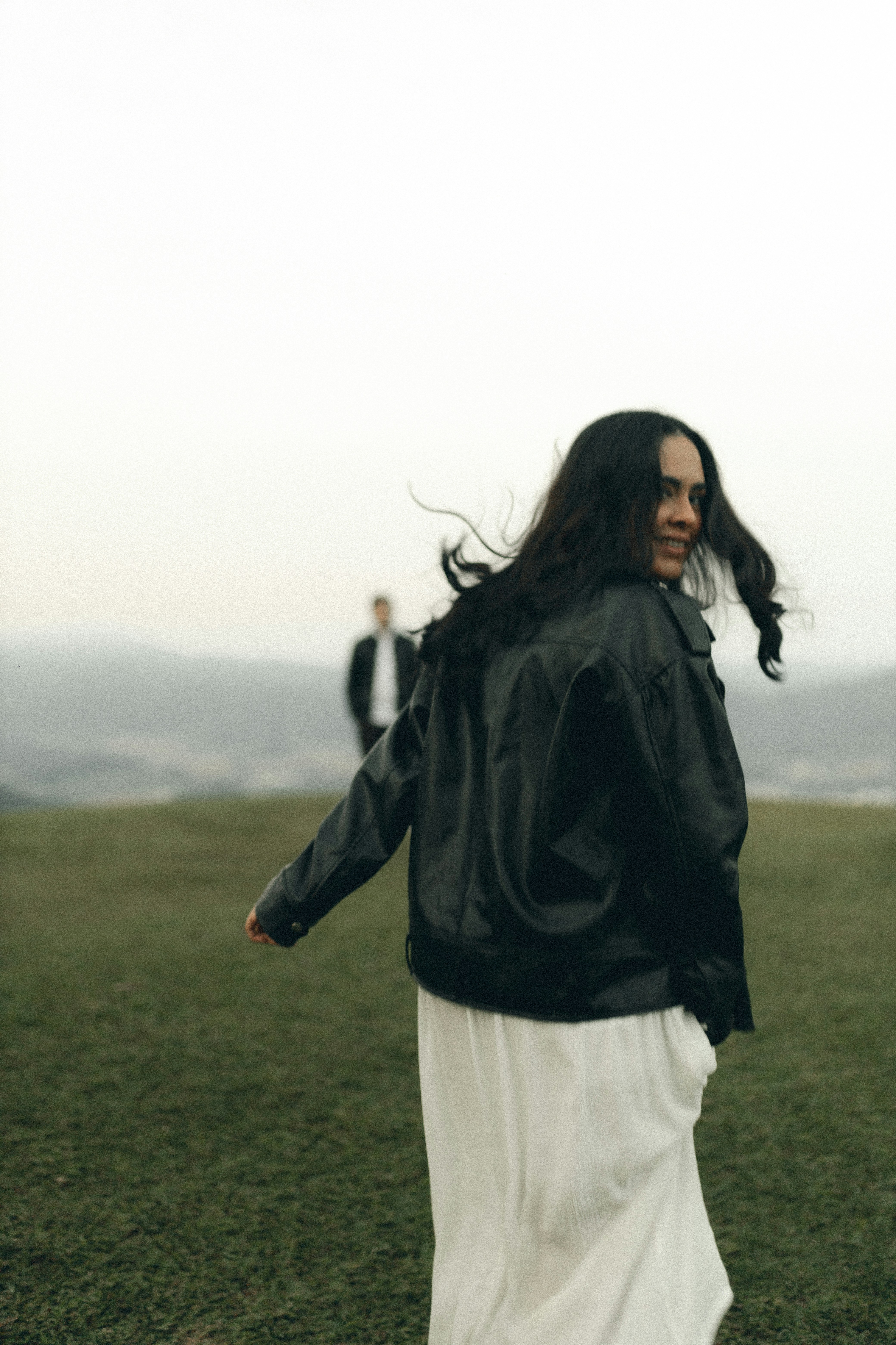 Woman in leather jacket looking back at man