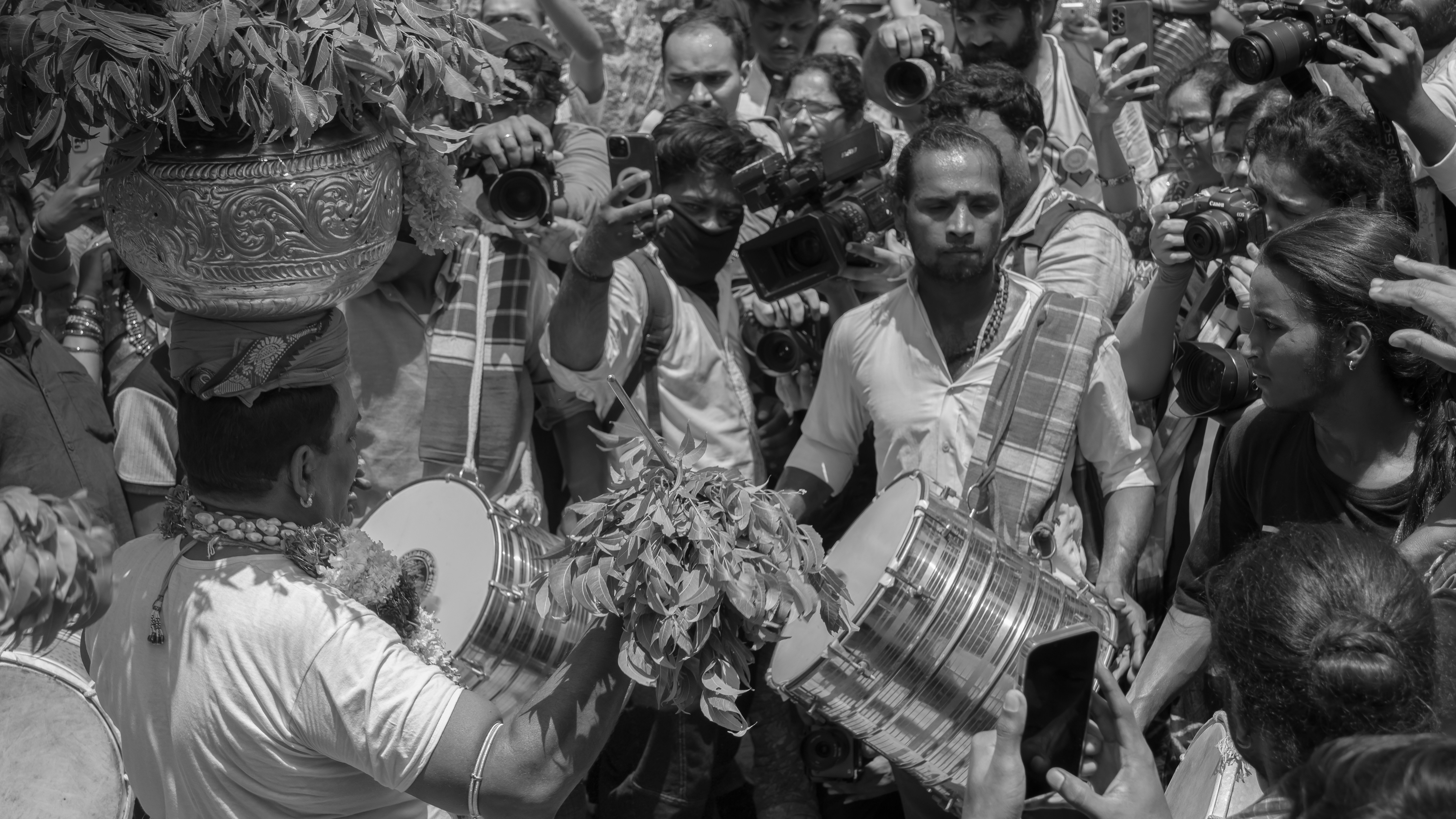 Two drummers engage in a lively performance surrounded by an enthusiastic crowd, capturing the essence of a vibrant cultural festival.