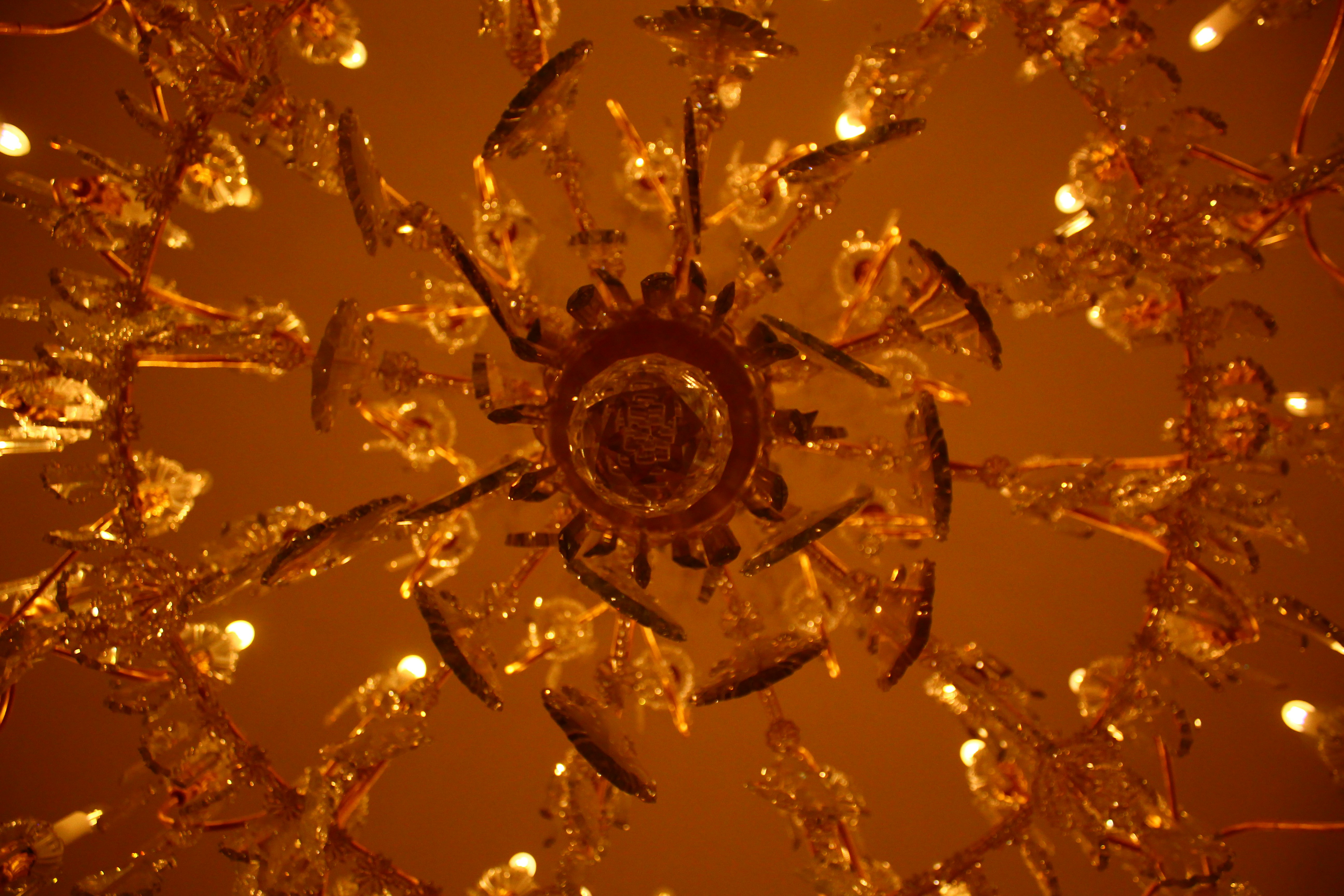 Intricate chandelier with shimmering crystals and warm lighting, viewed from below. The design creates a mesmerizing spiral effect.