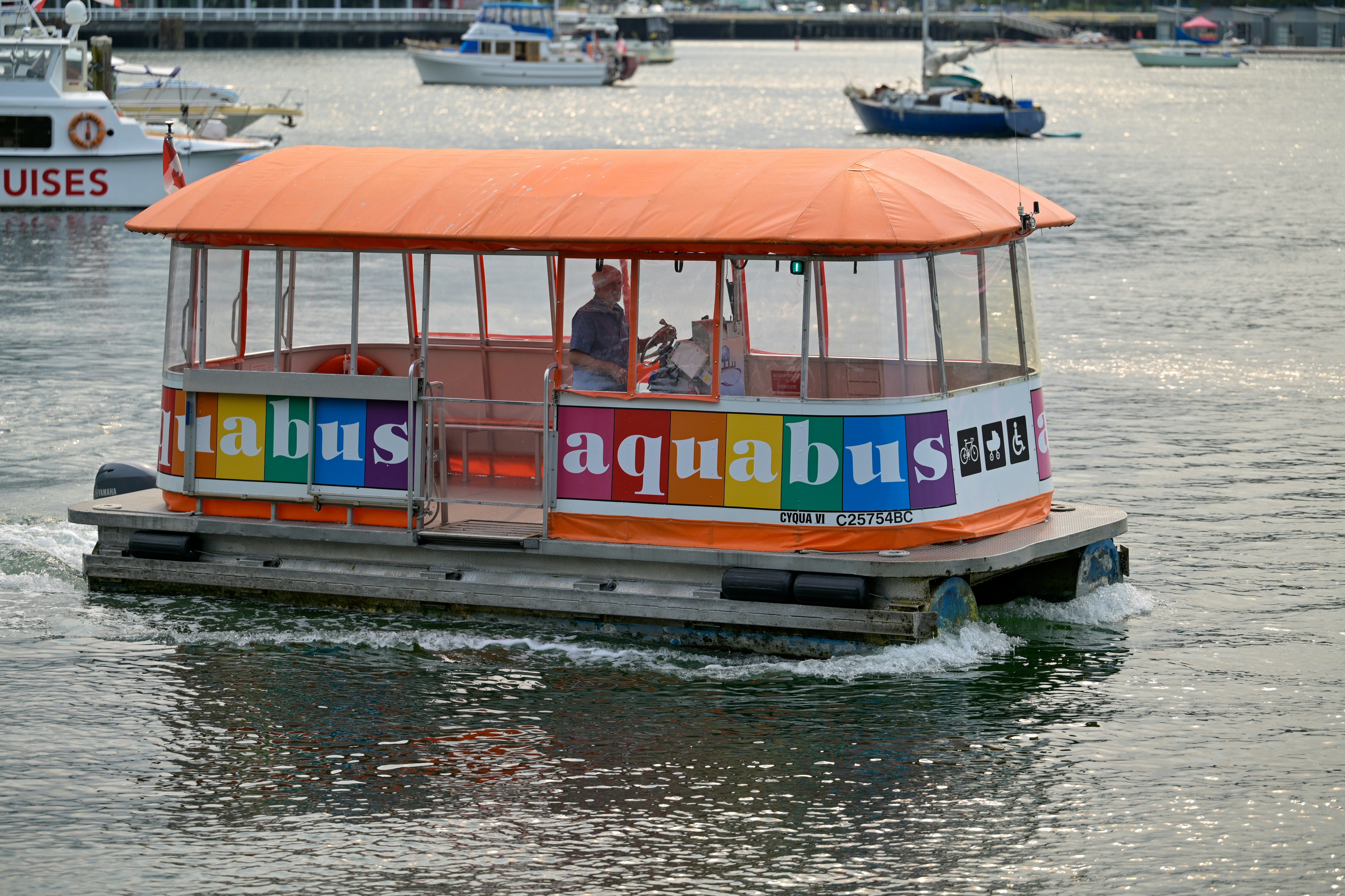 Orange-roofed Aqua Bus Gliding Across Gentle Dockside Wake