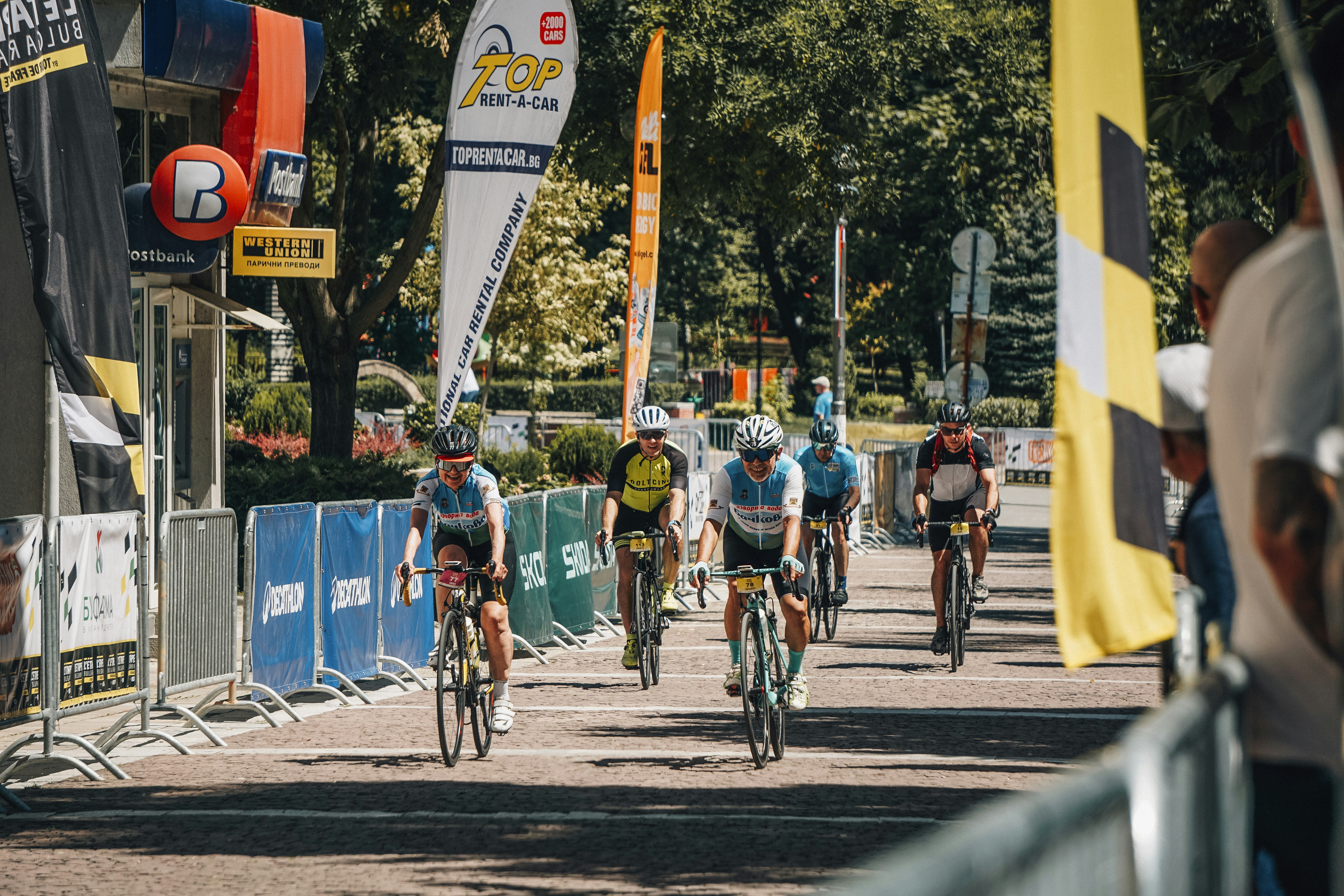 Breakaway Through Bannered Streets: Blue-Jersey Cyclists Surge Forward