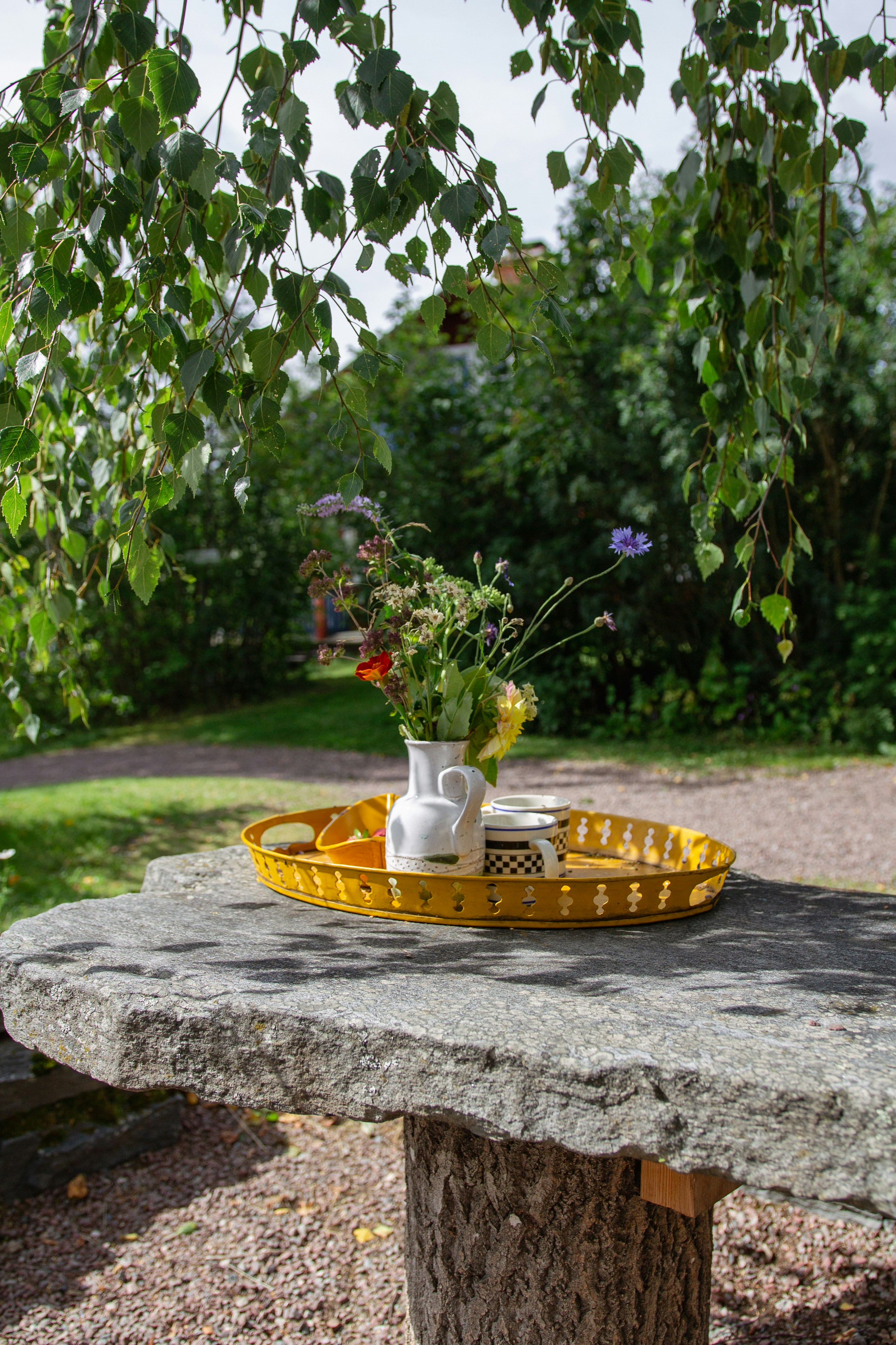A tray with flowers and food on a stone table.
