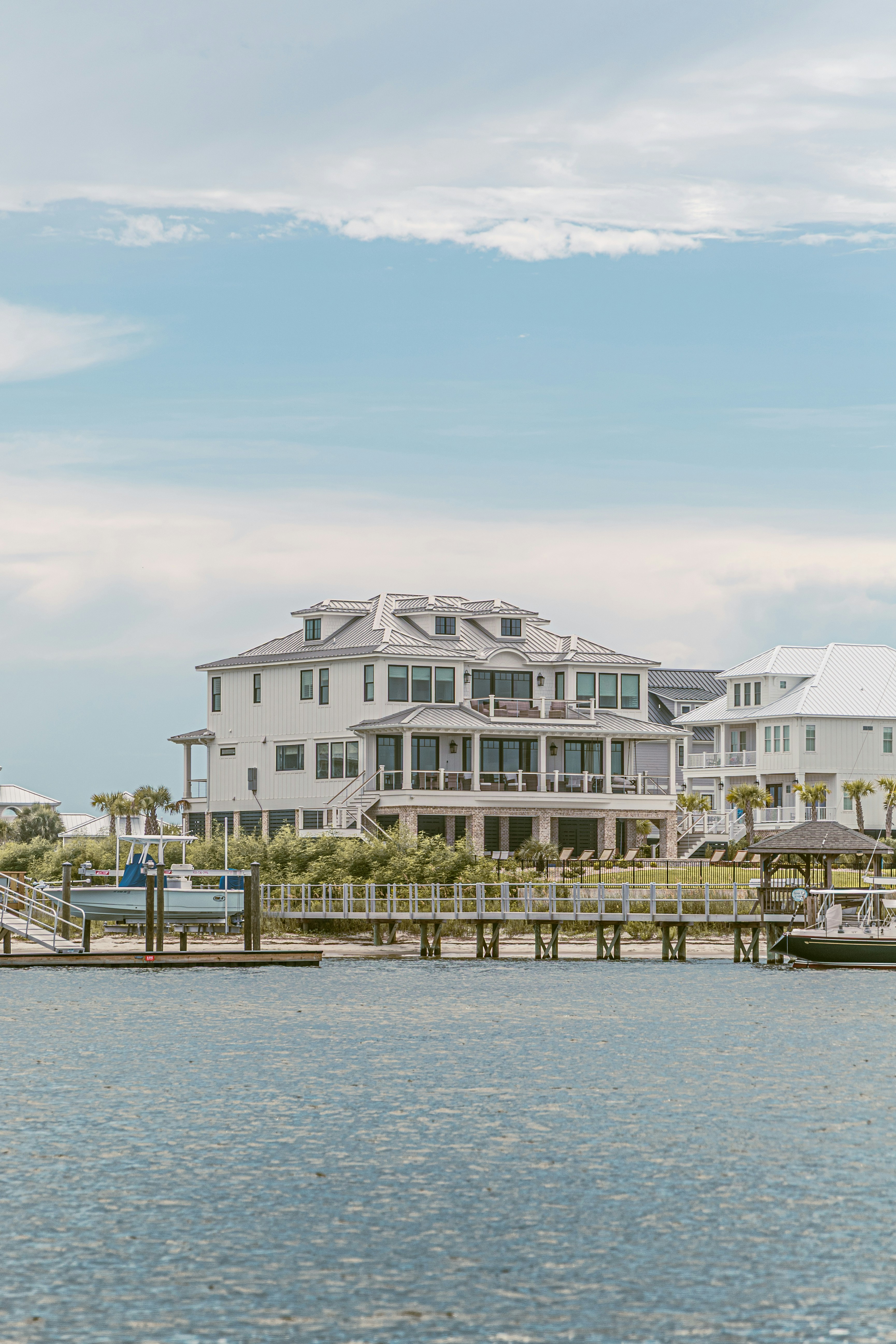 A nice house on the shoreline in Murrels Inlet, SC. Captured from the water on a boat. | Large white house on the water with dock