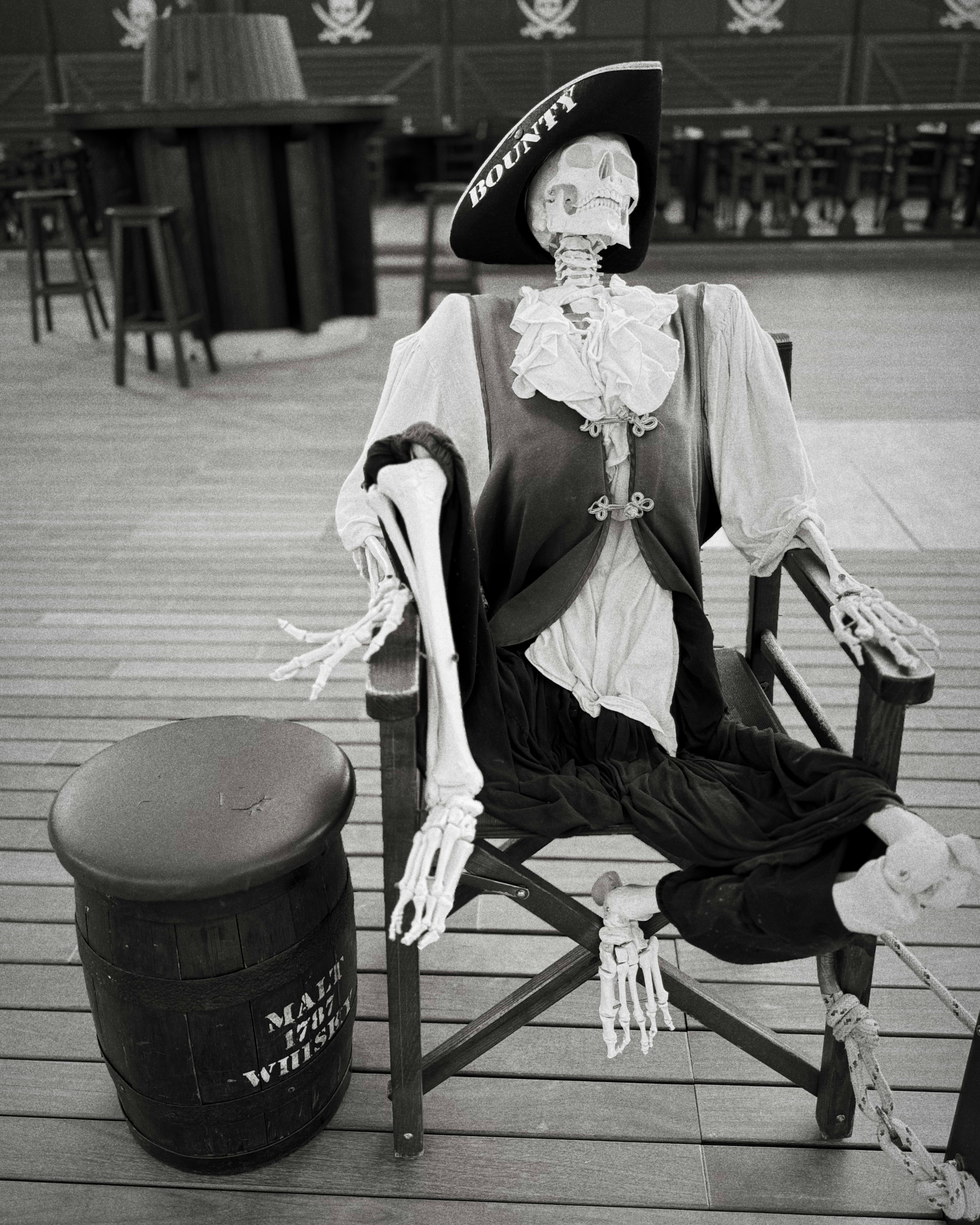 Skeleton pirate sitting on a chair with a barrel