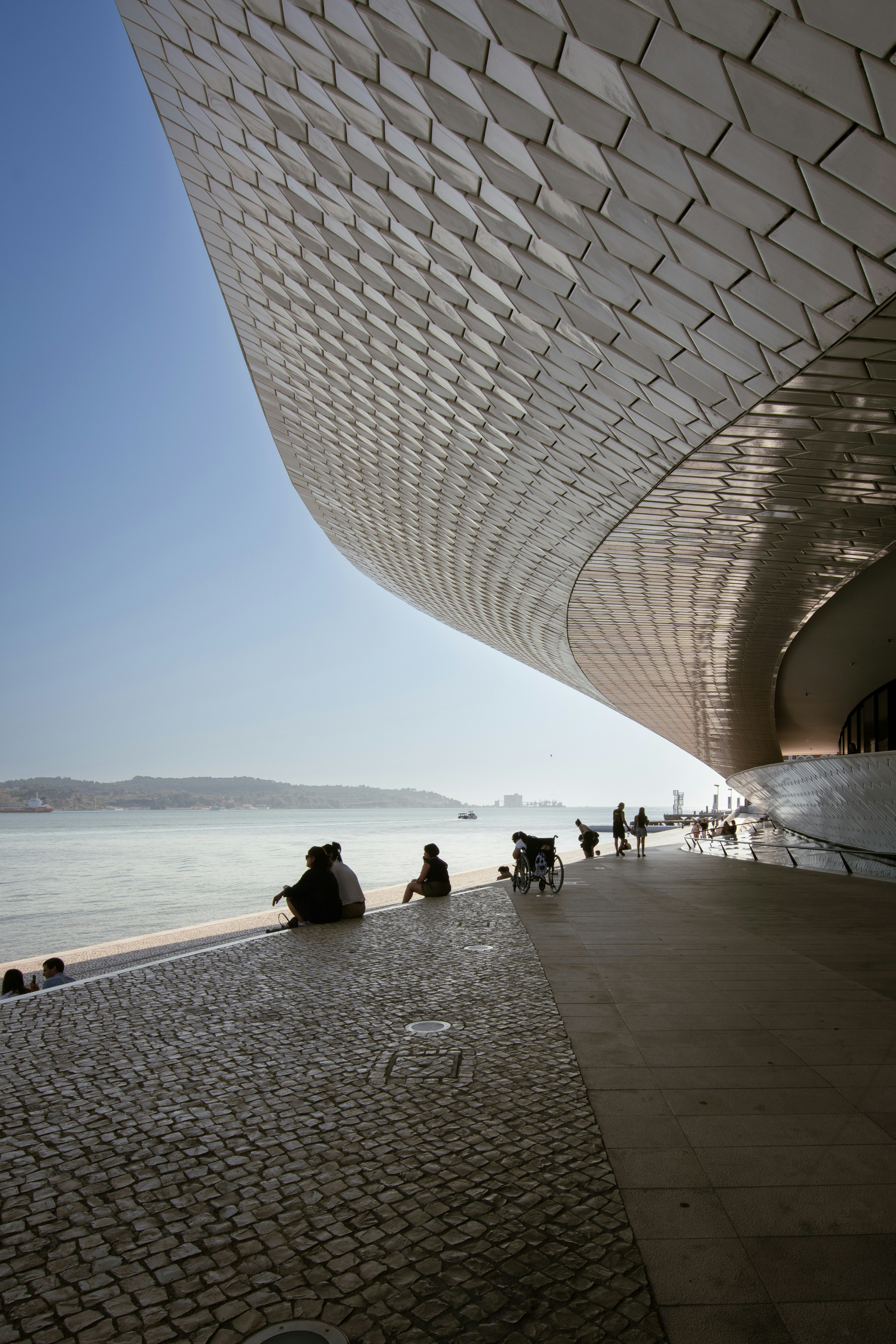 Modern building with waterfront promenade and people