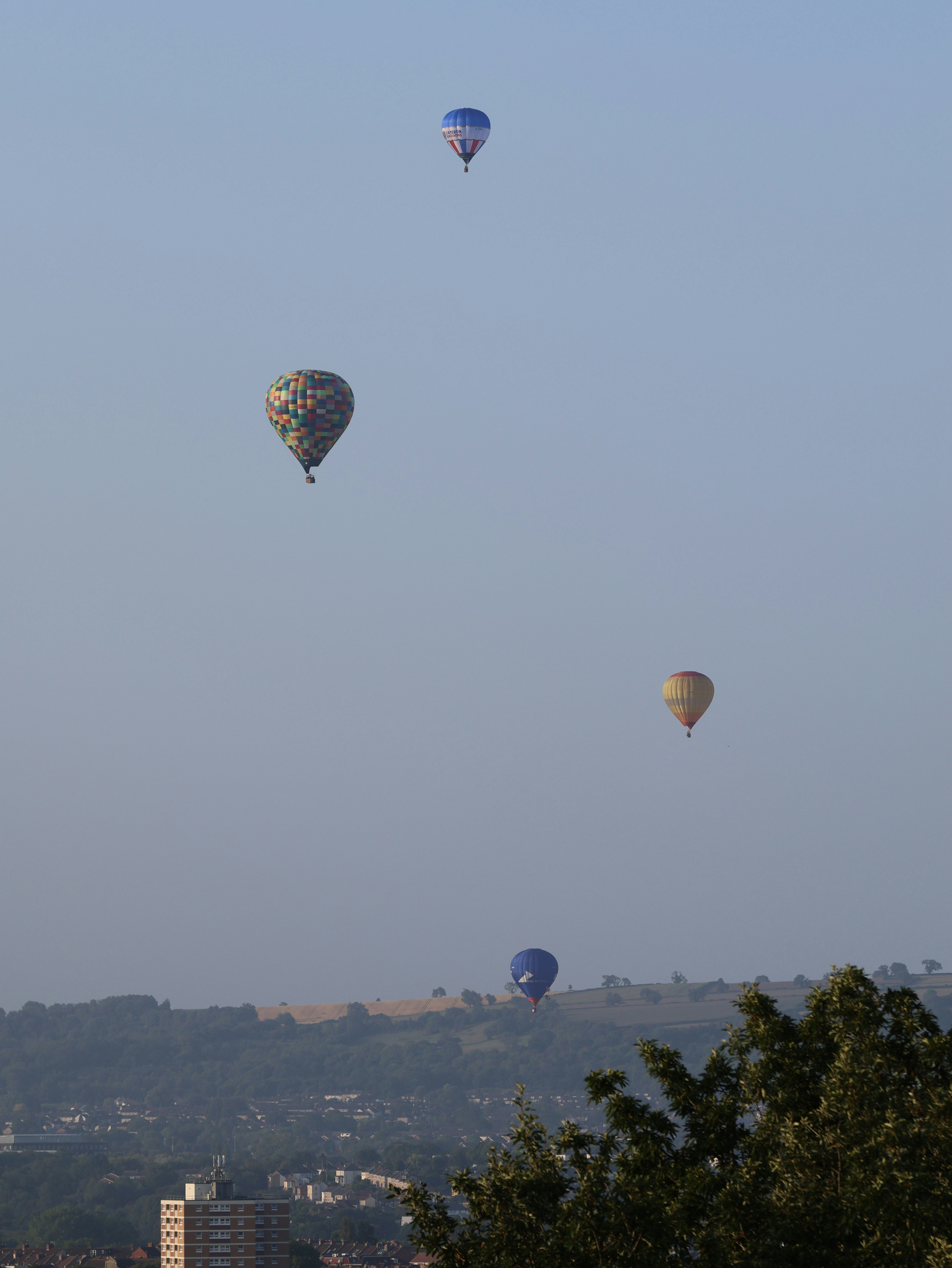 Four hot air balloons ascend into a clear sky.