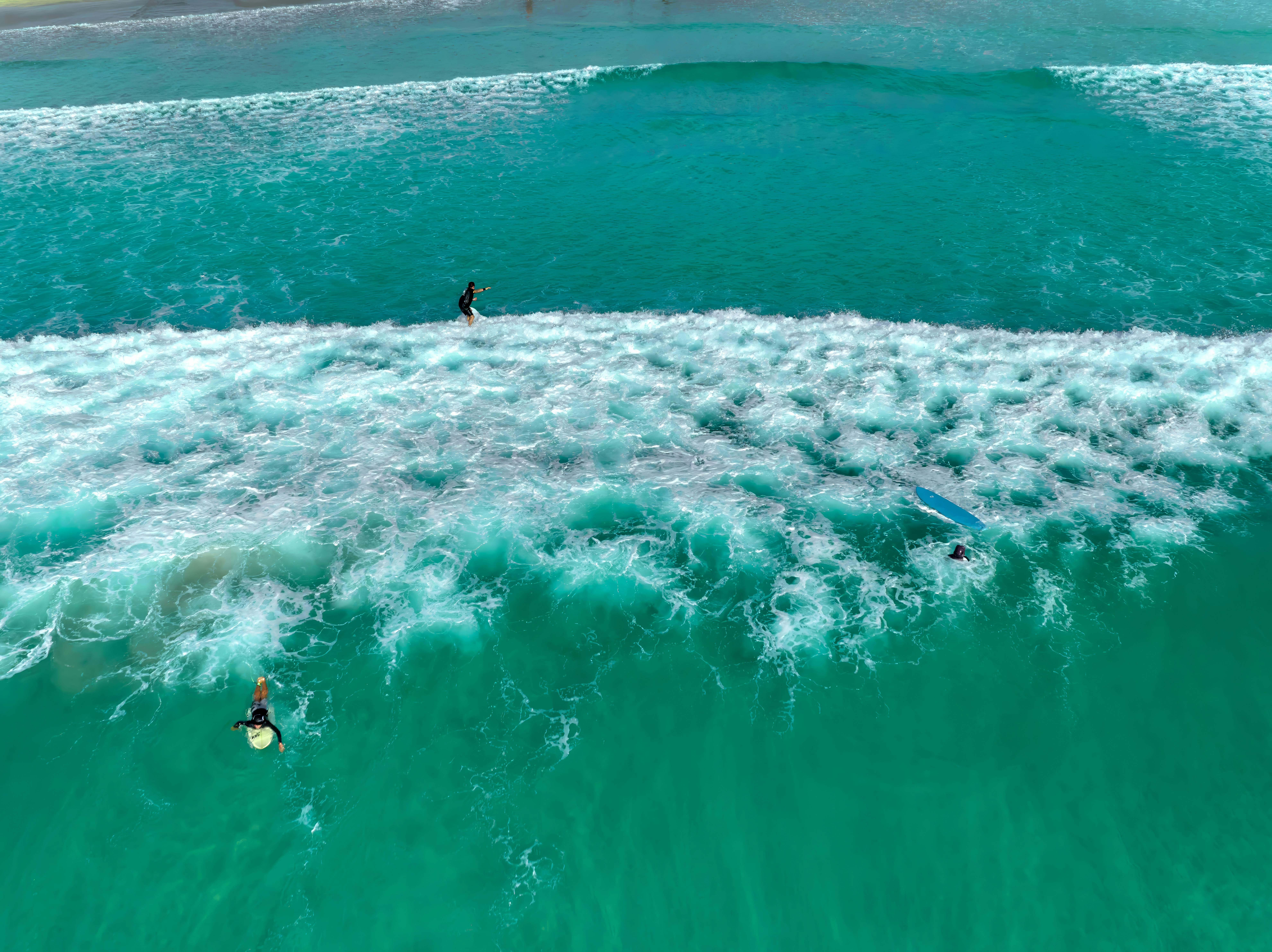 Emerald Channel Ride: Aerial View of Surfers Cutting Through Turquoise Break