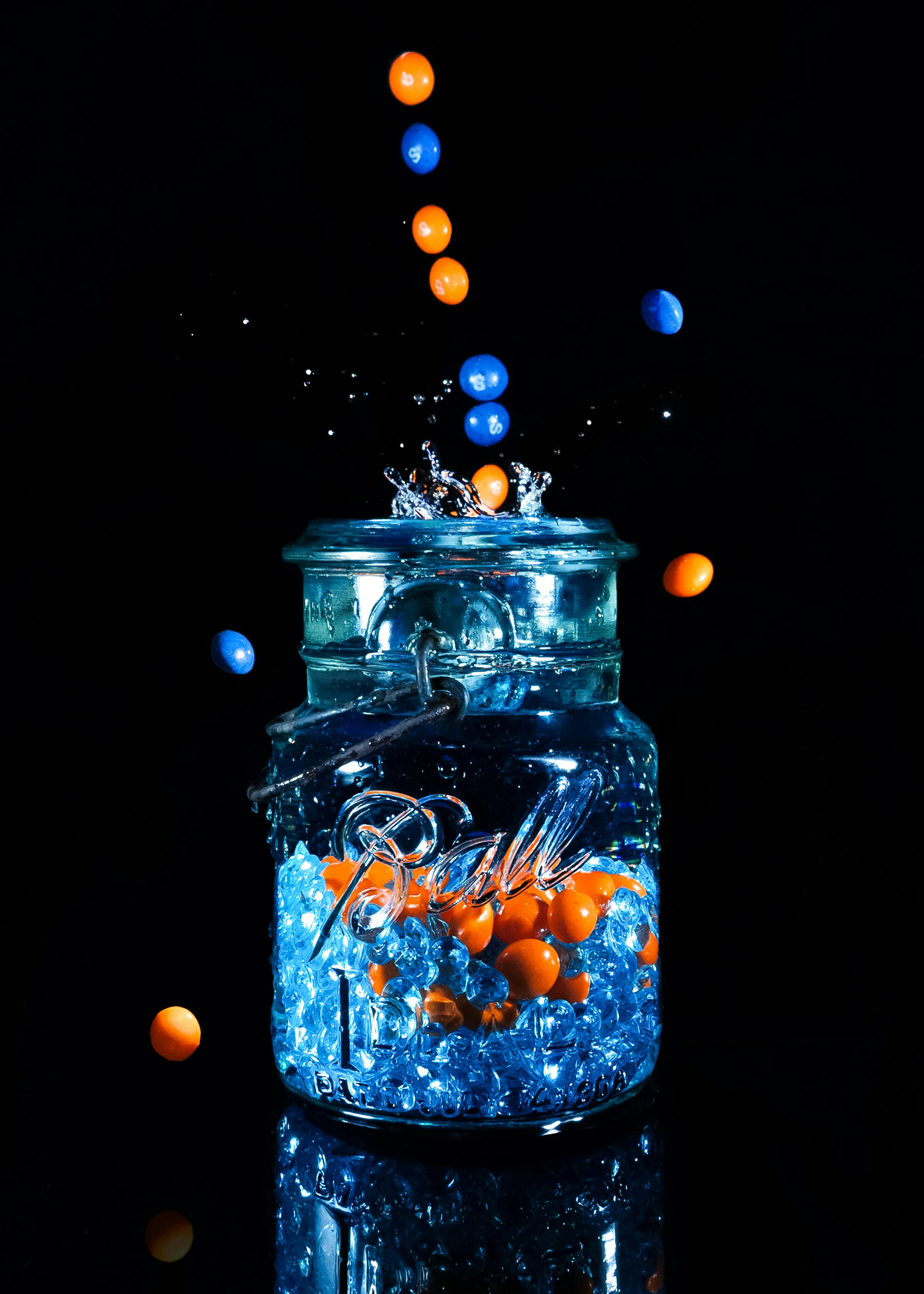 Orange and blue candies splashing into a jar