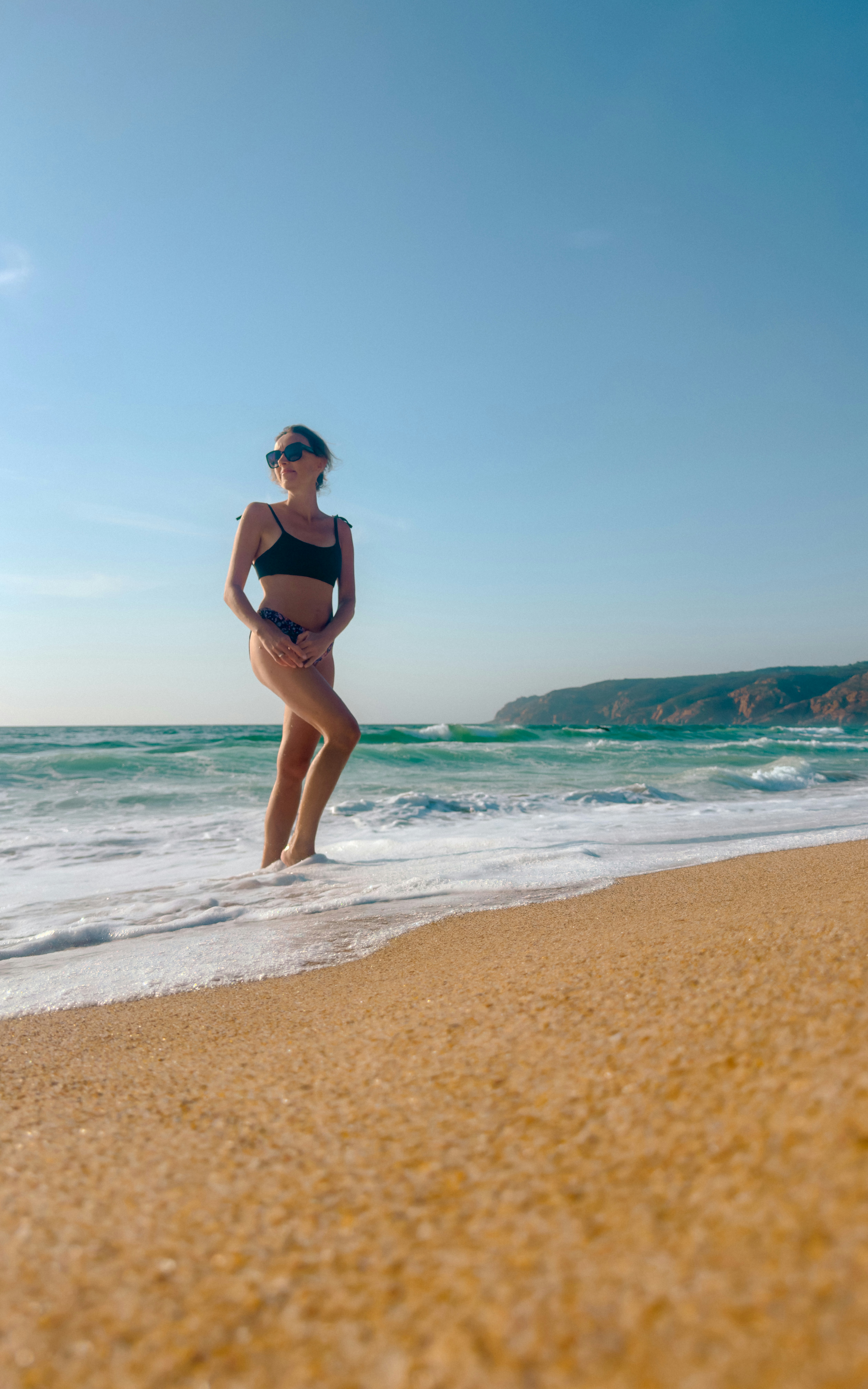 Woman in bikini standing at the ocean shore