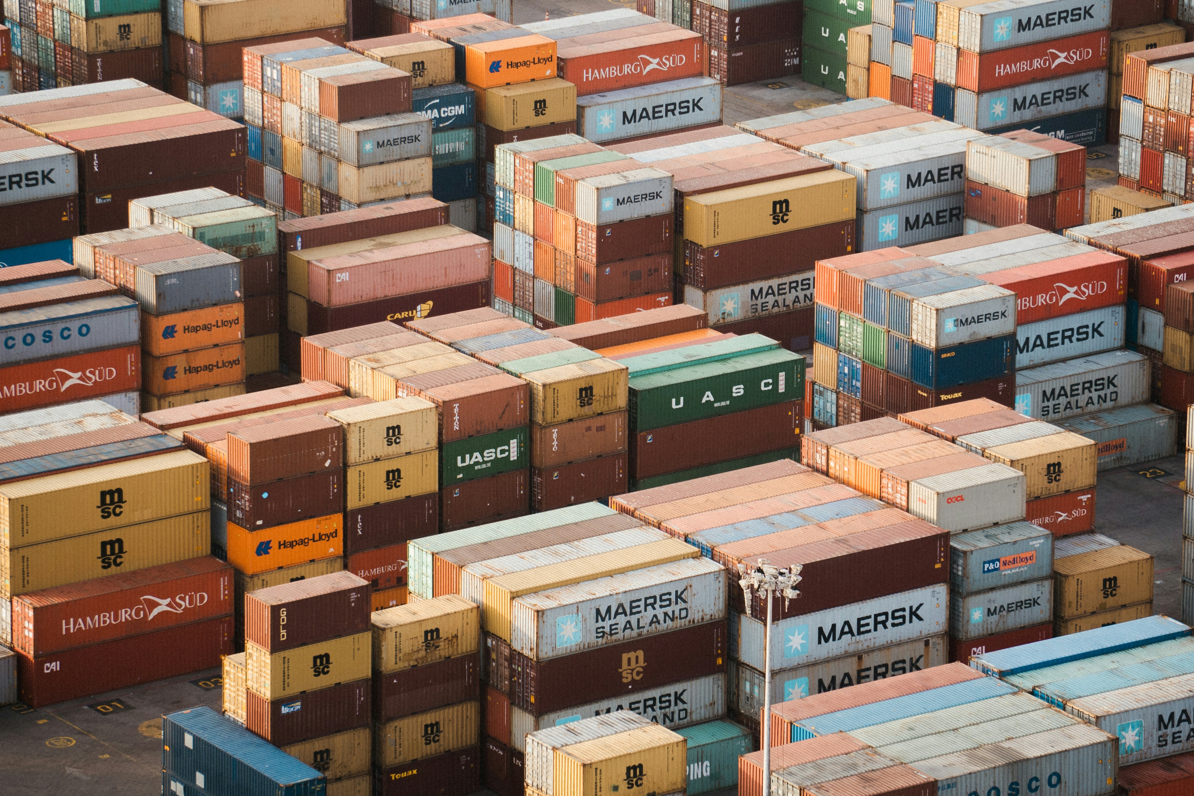 Many stacked shipping containers at a port.