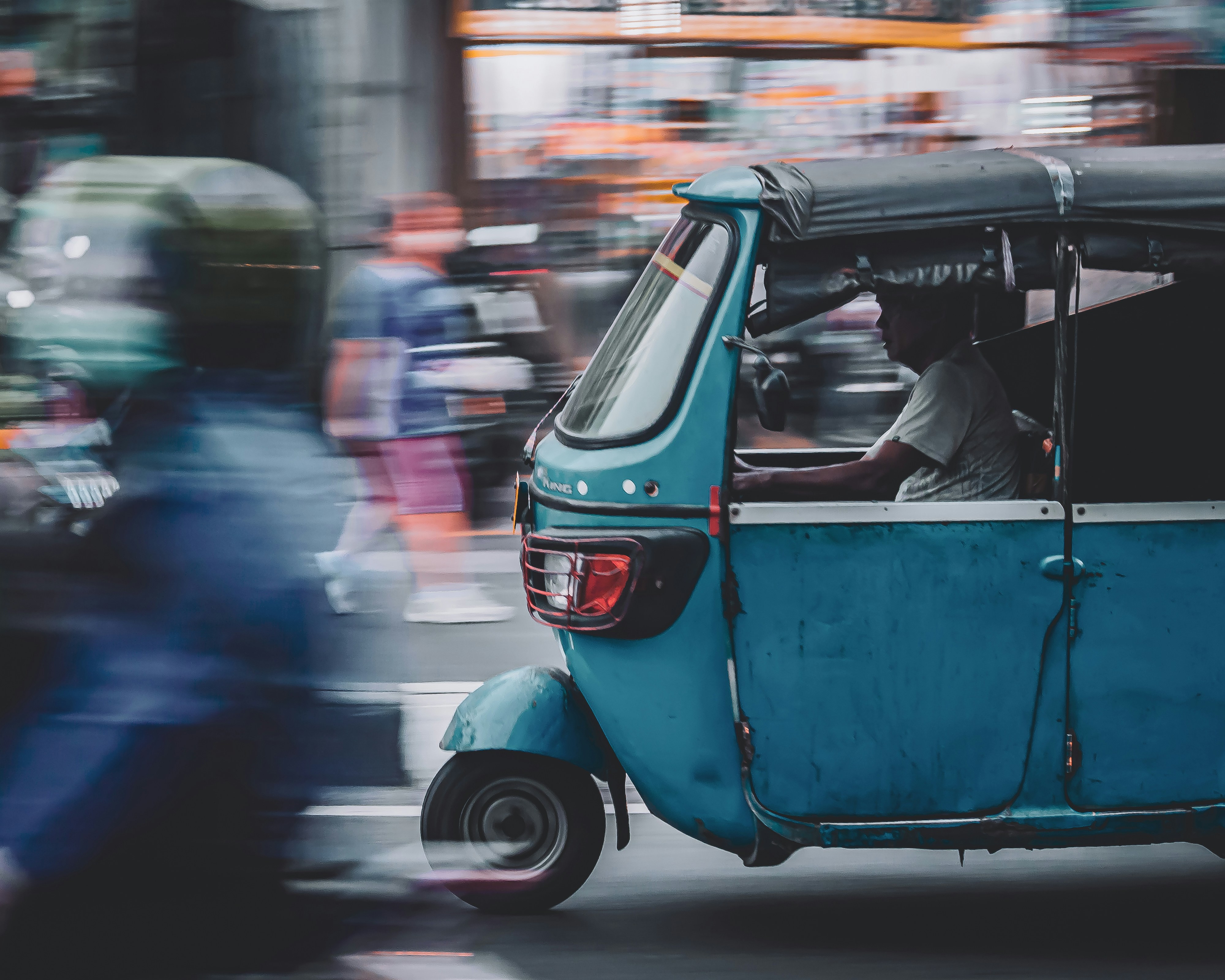 Panning shot of a Bajaj in a busy street in Jakarta | Blue auto rickshaw driving on a busy street