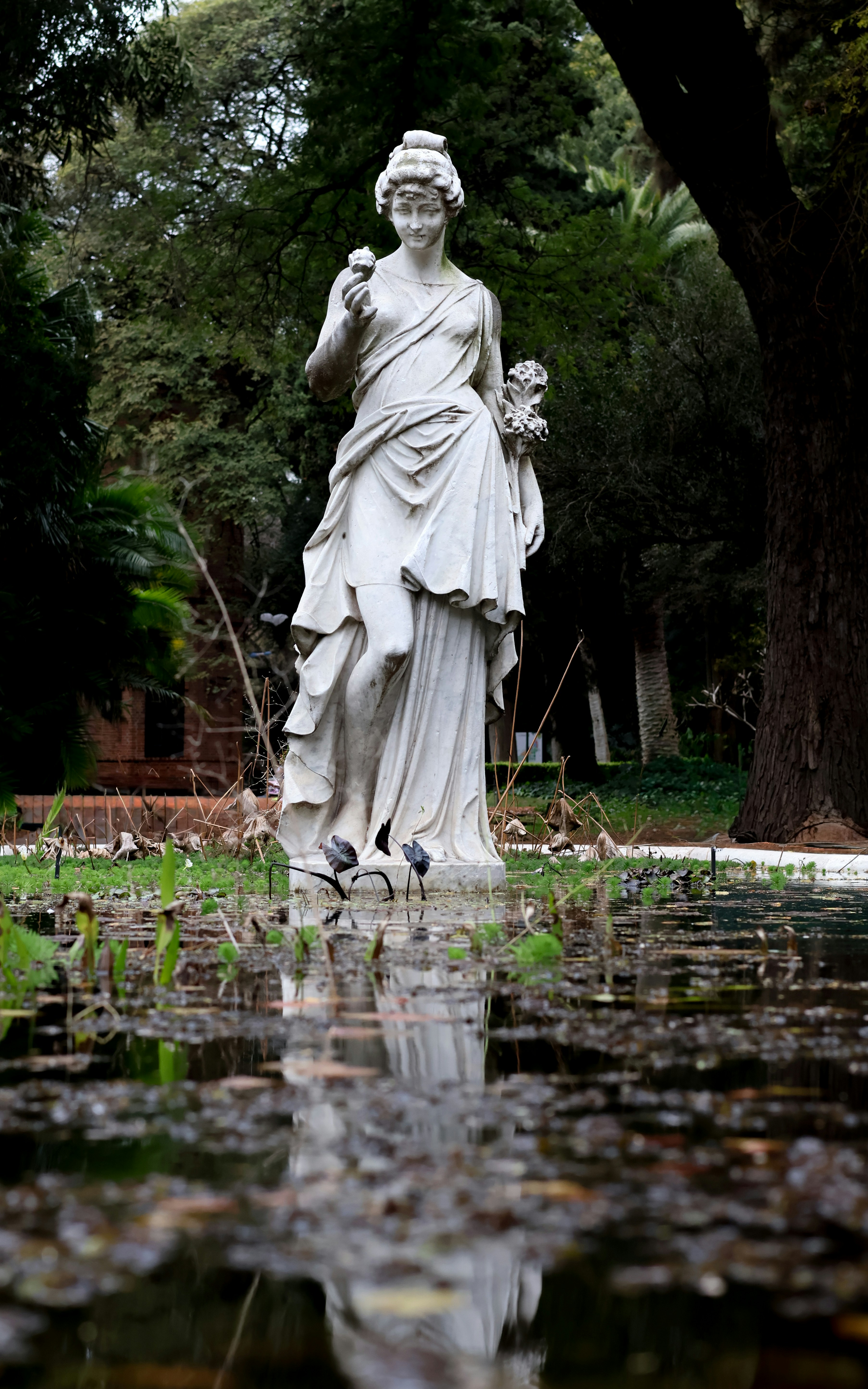 White marble statue of a woman in a garden