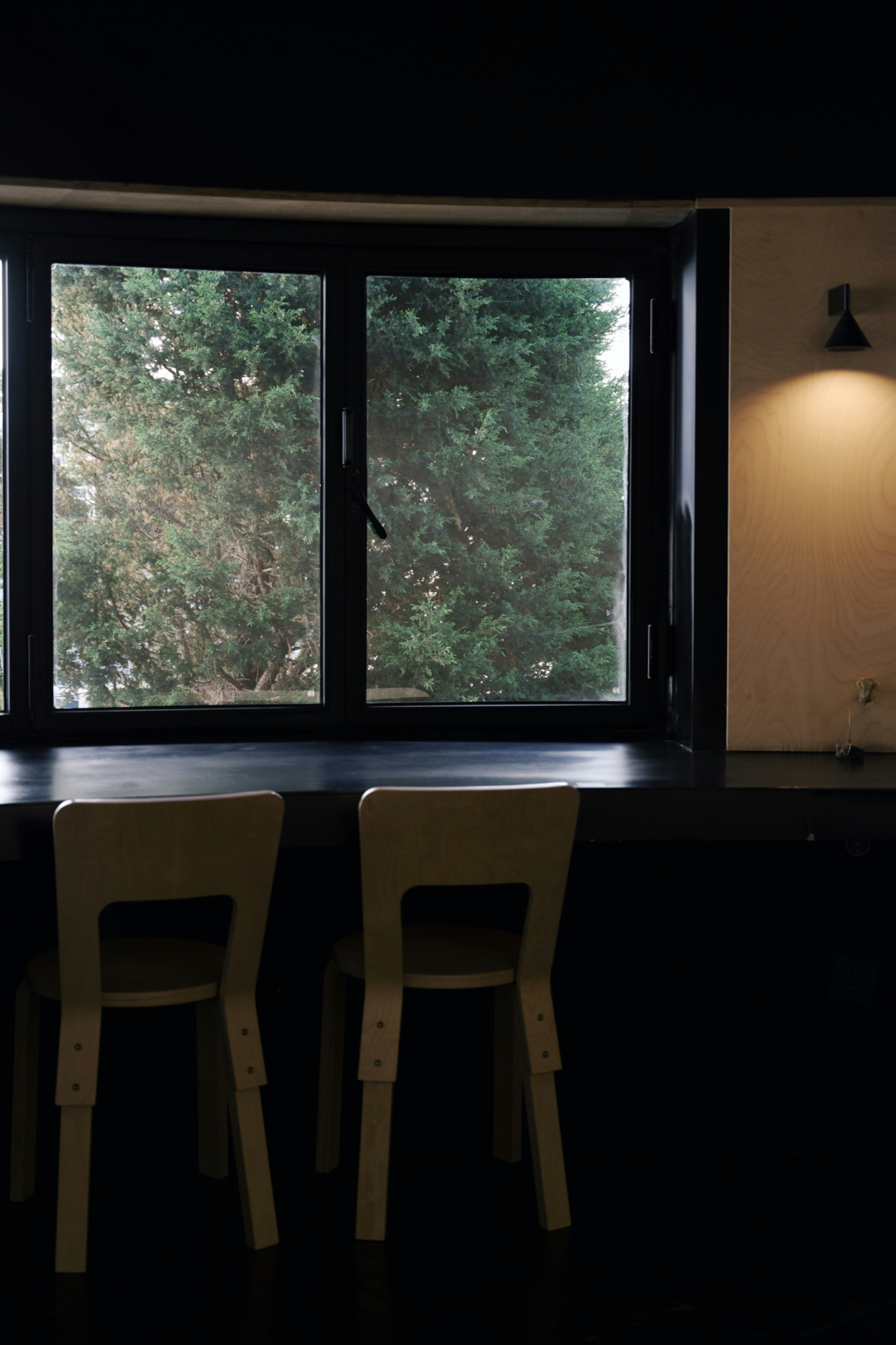 Two chairs at a window overlooking trees