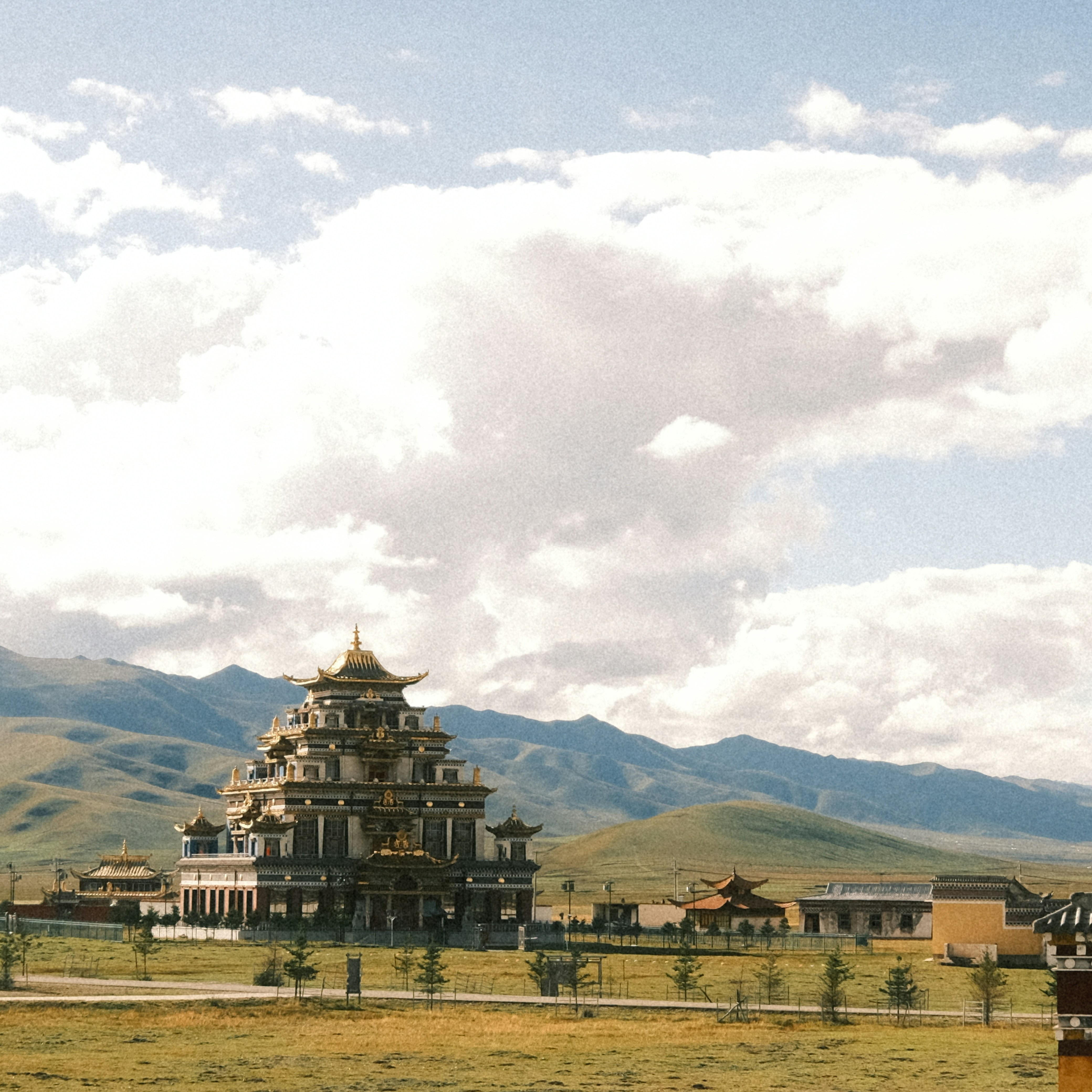 A majestic temple stands against a backdrop of rolling hills and a vibrant sky, showcasing intricate architecture amidst serene landscapes.
