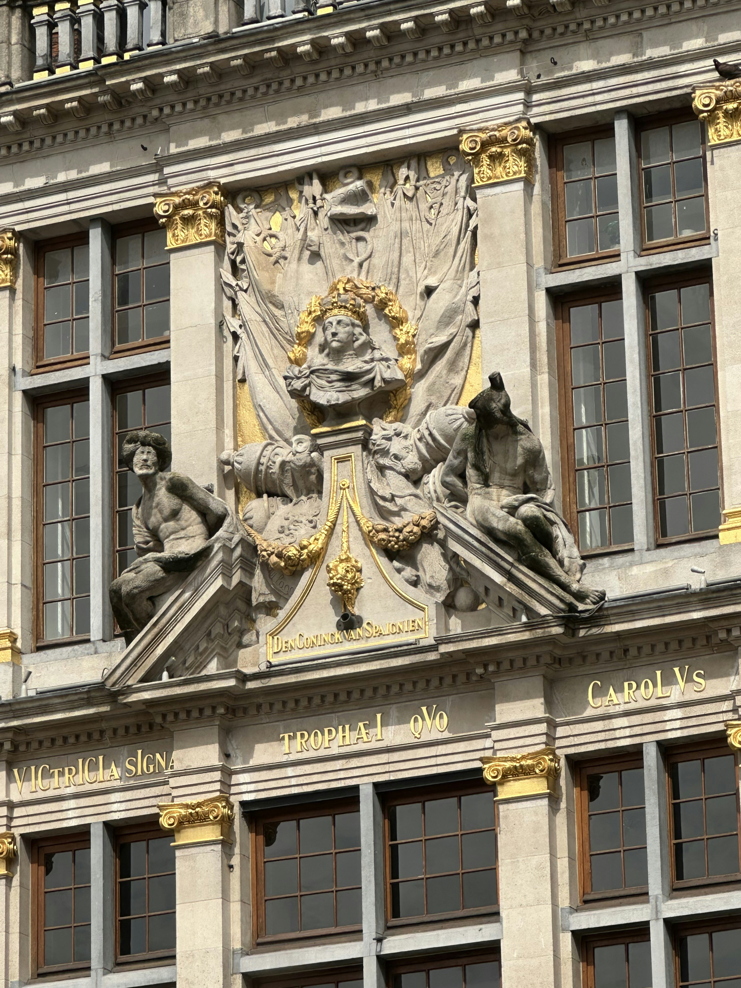 Intricate stone relief featuring historical figures and ornate decorations on a building facade.