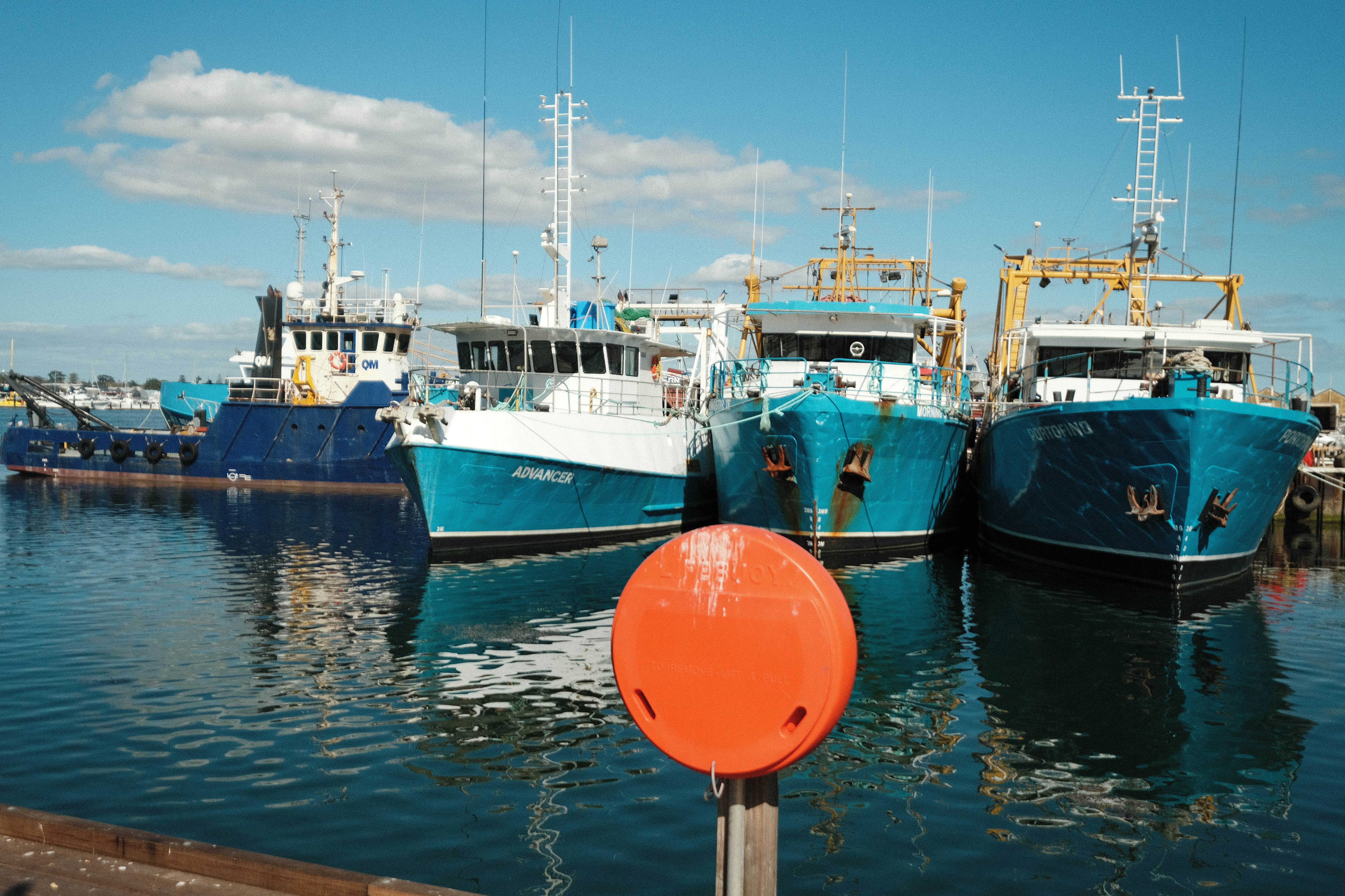 Several blue fishing boats docked in a harbor.