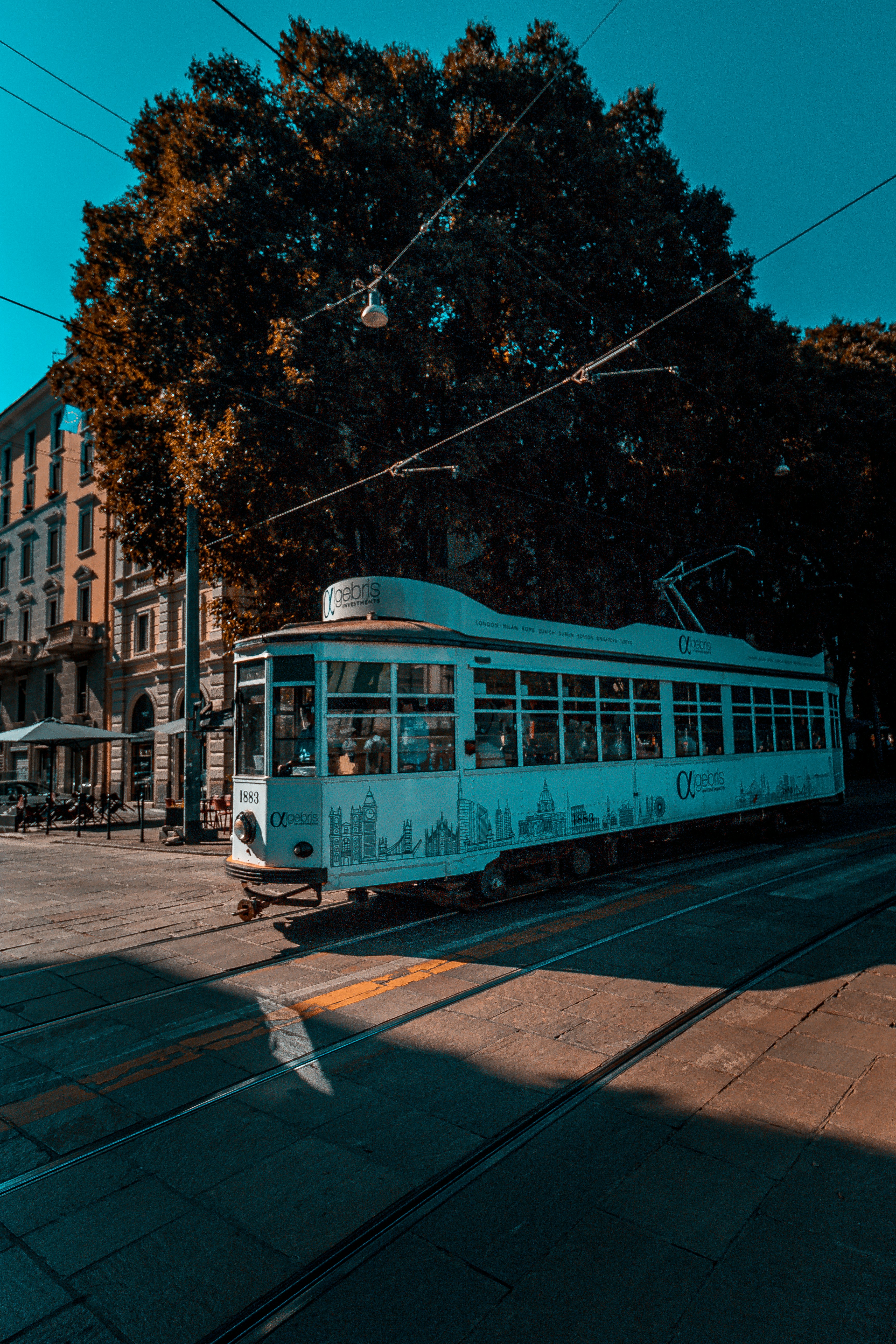 A white tram travels down city tracks.