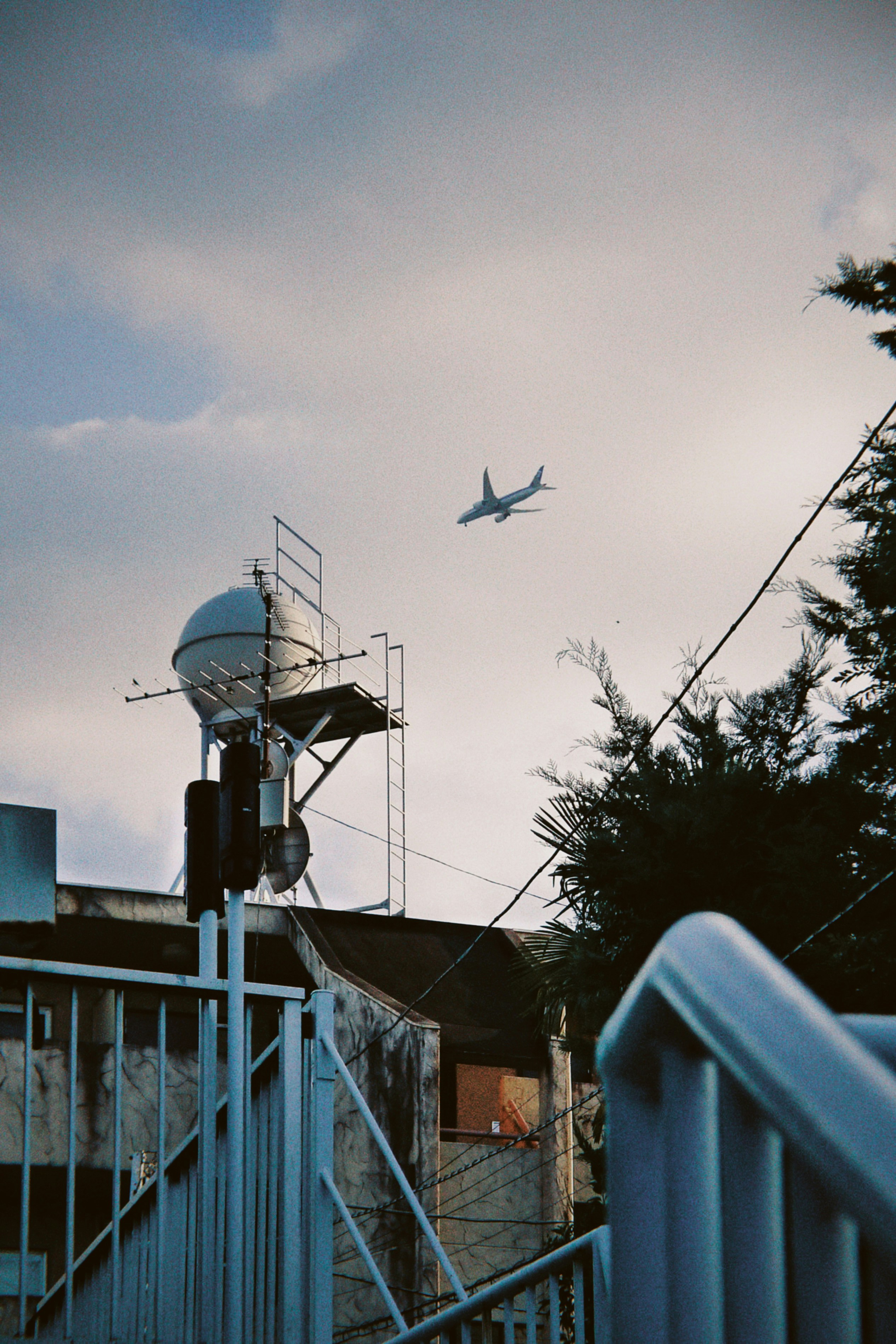 Airplane flying over urban structures at dusk