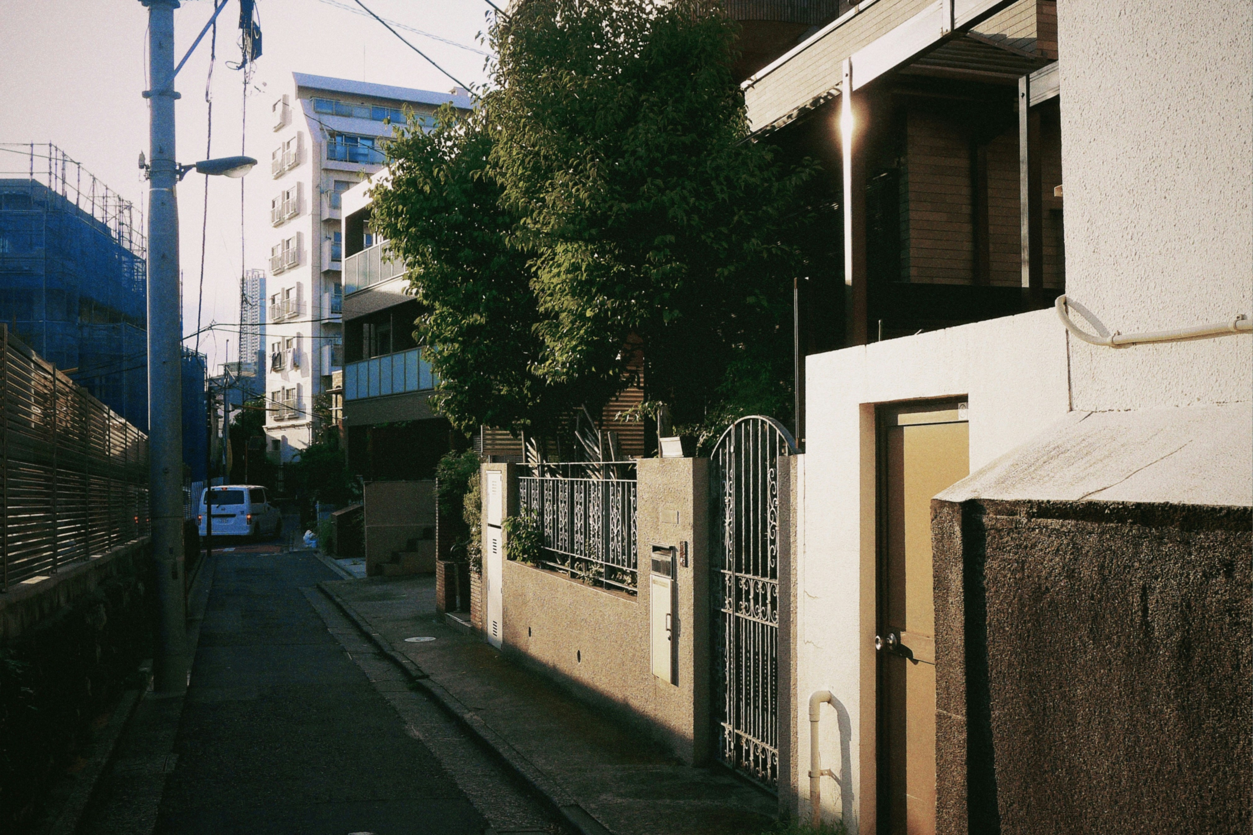 Narrow street between buildings with trees and fence