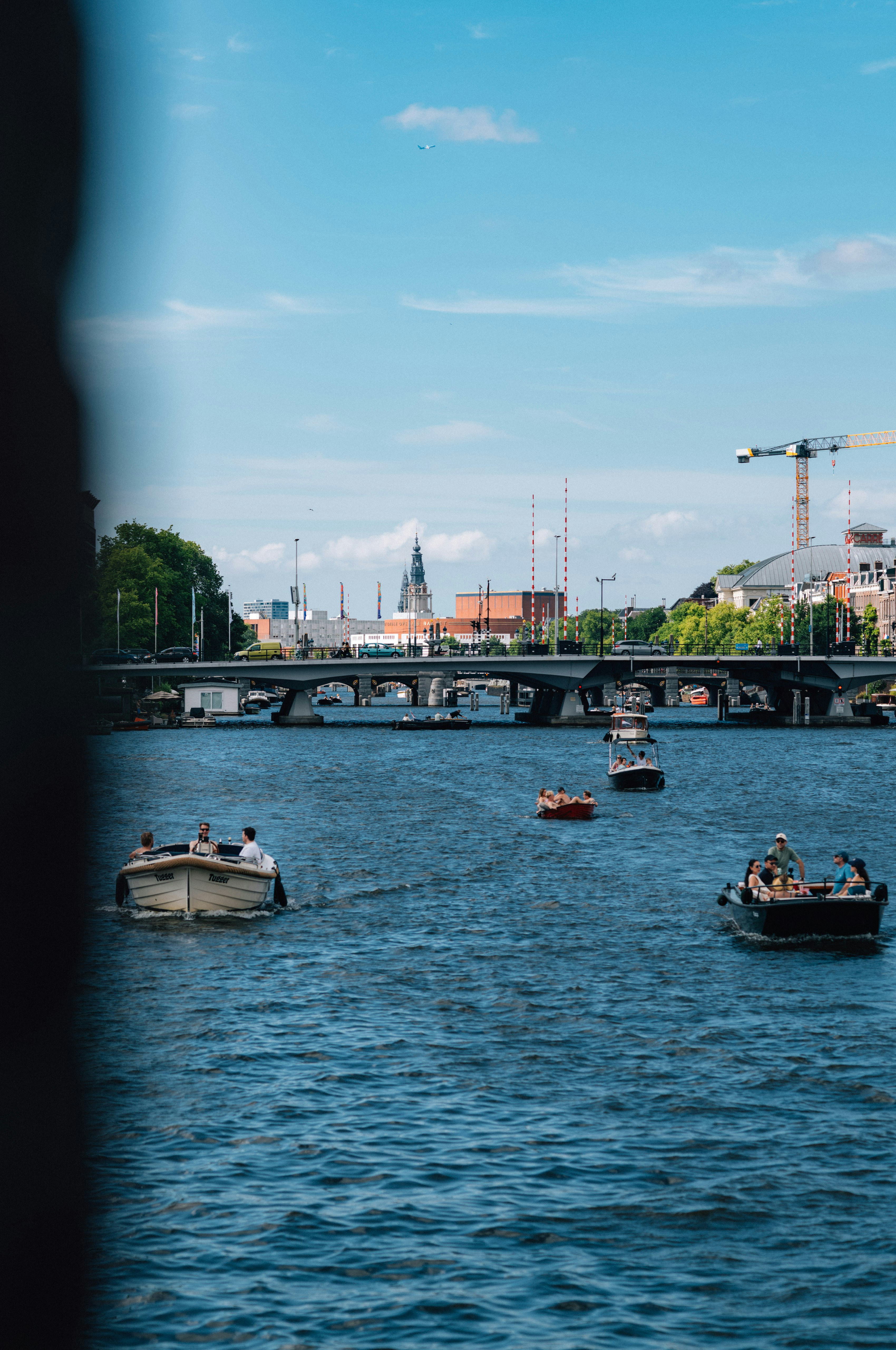 Boats on a river with a bridge and city skyline.