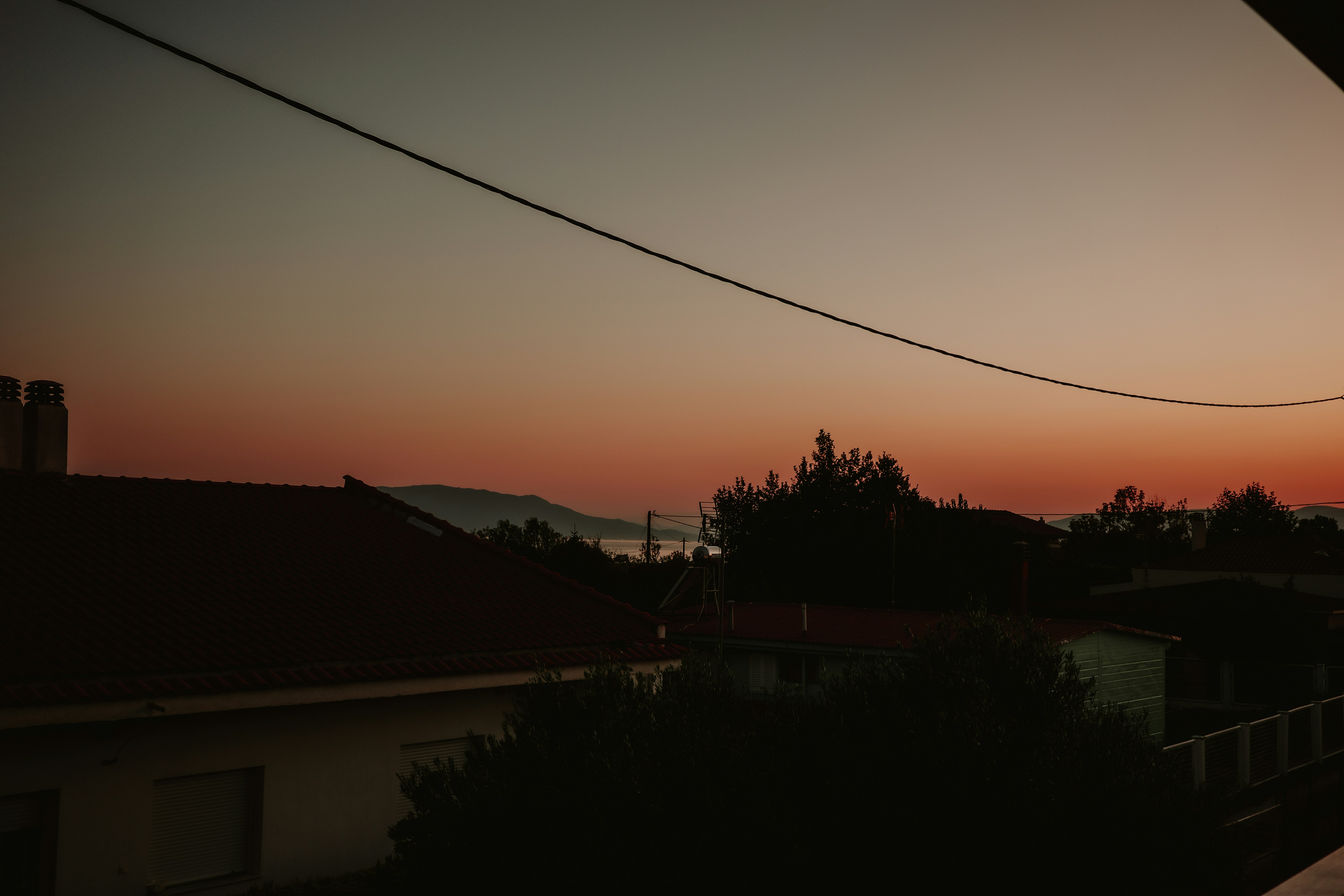 Sunset over rooftops with distant trees and water