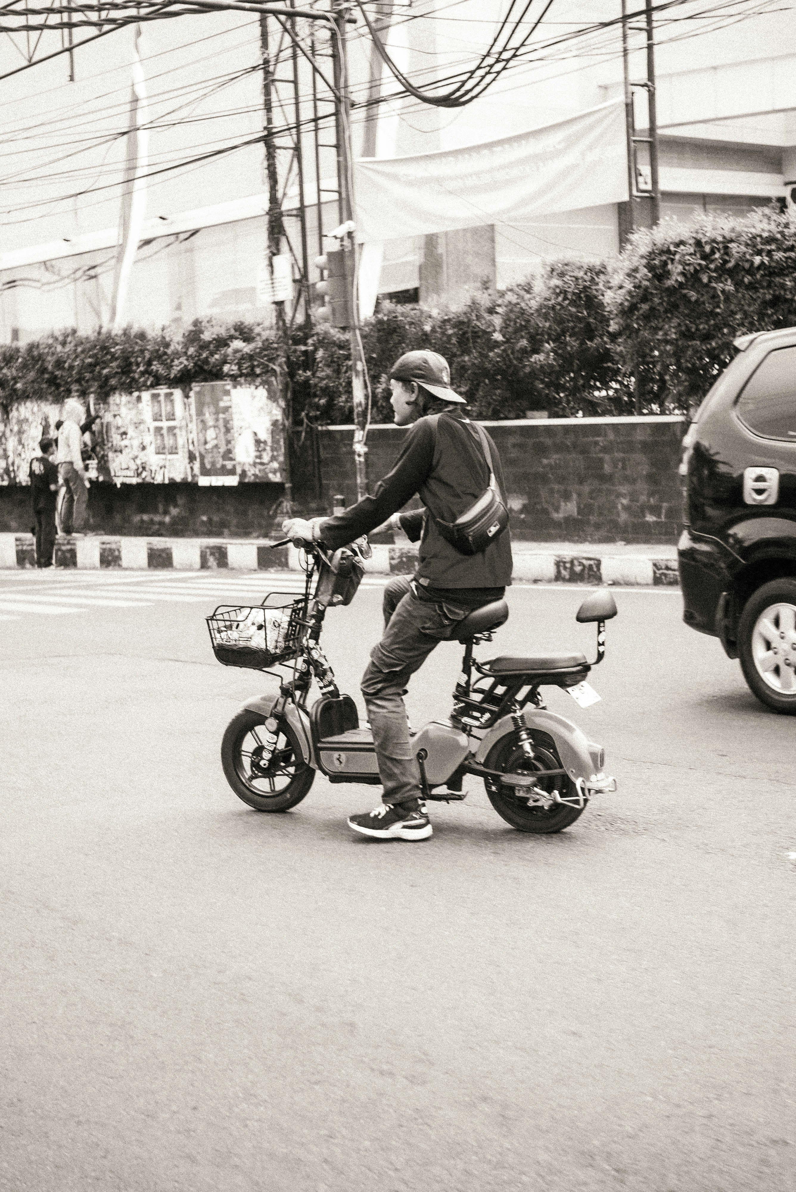 Man riding an electric scooter through a city street.