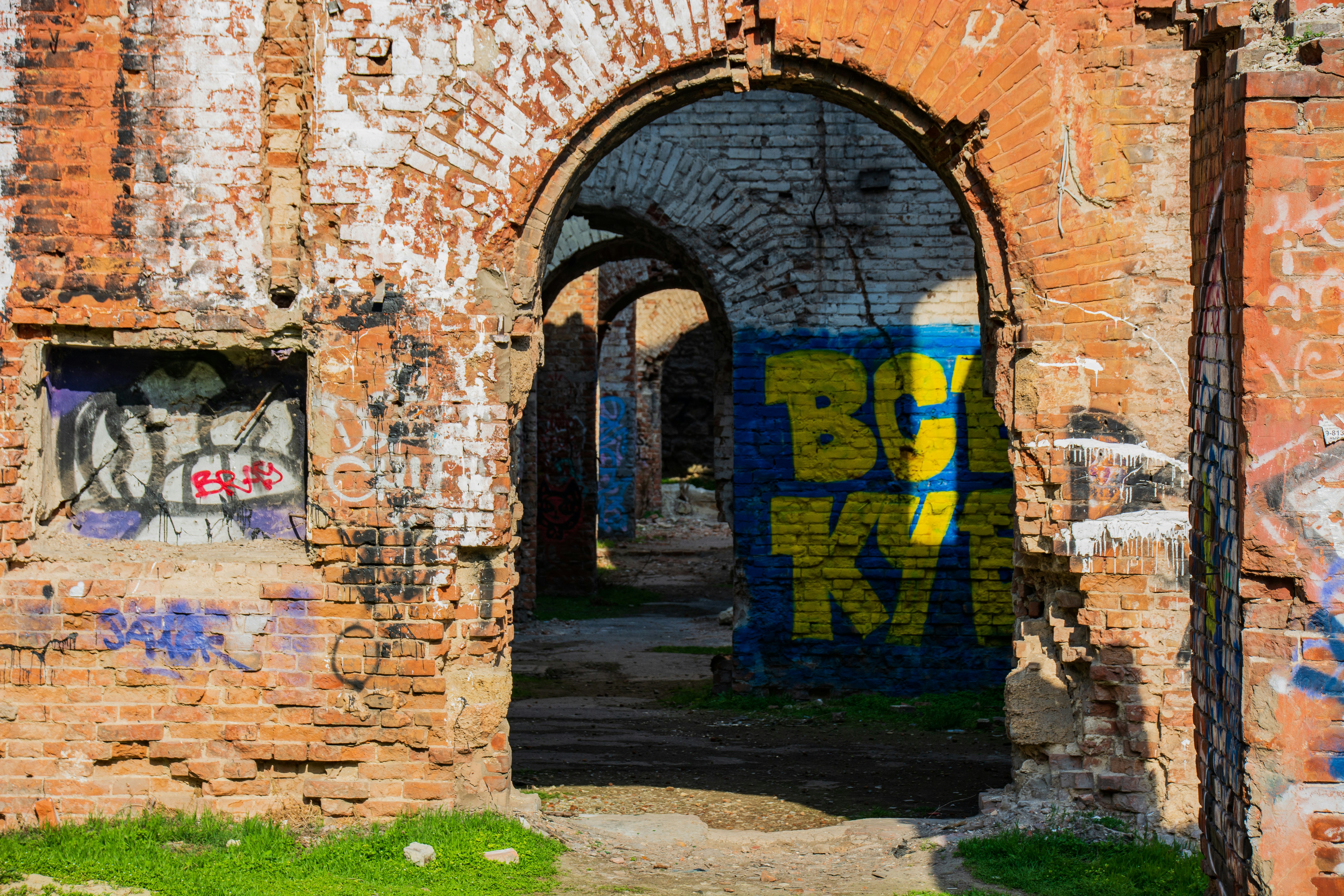 Vivid graffiti adorns the weathered brick walls of an abandoned structure, showcasing urban art amidst crumbling architecture.