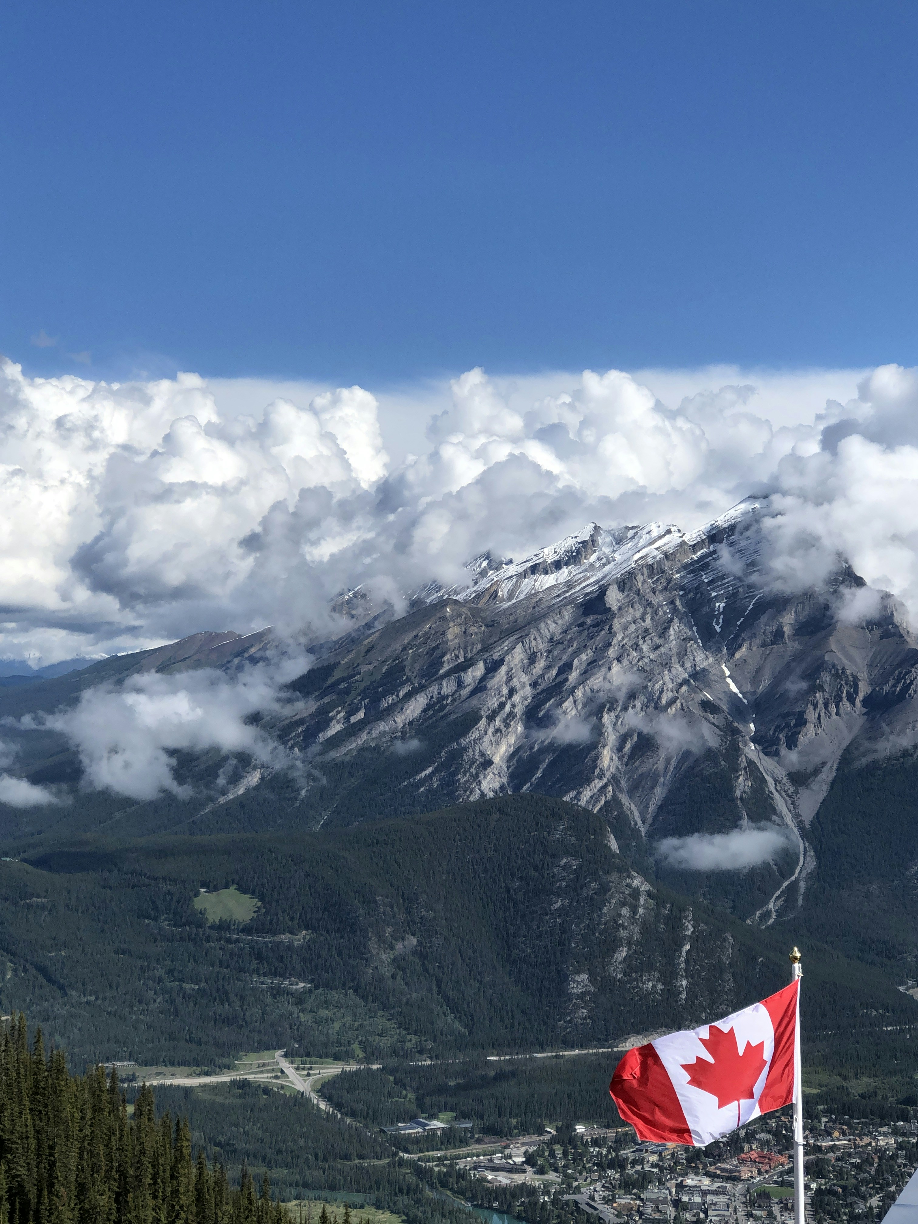 Canadian flag flies over a majestic mountain landscape.
