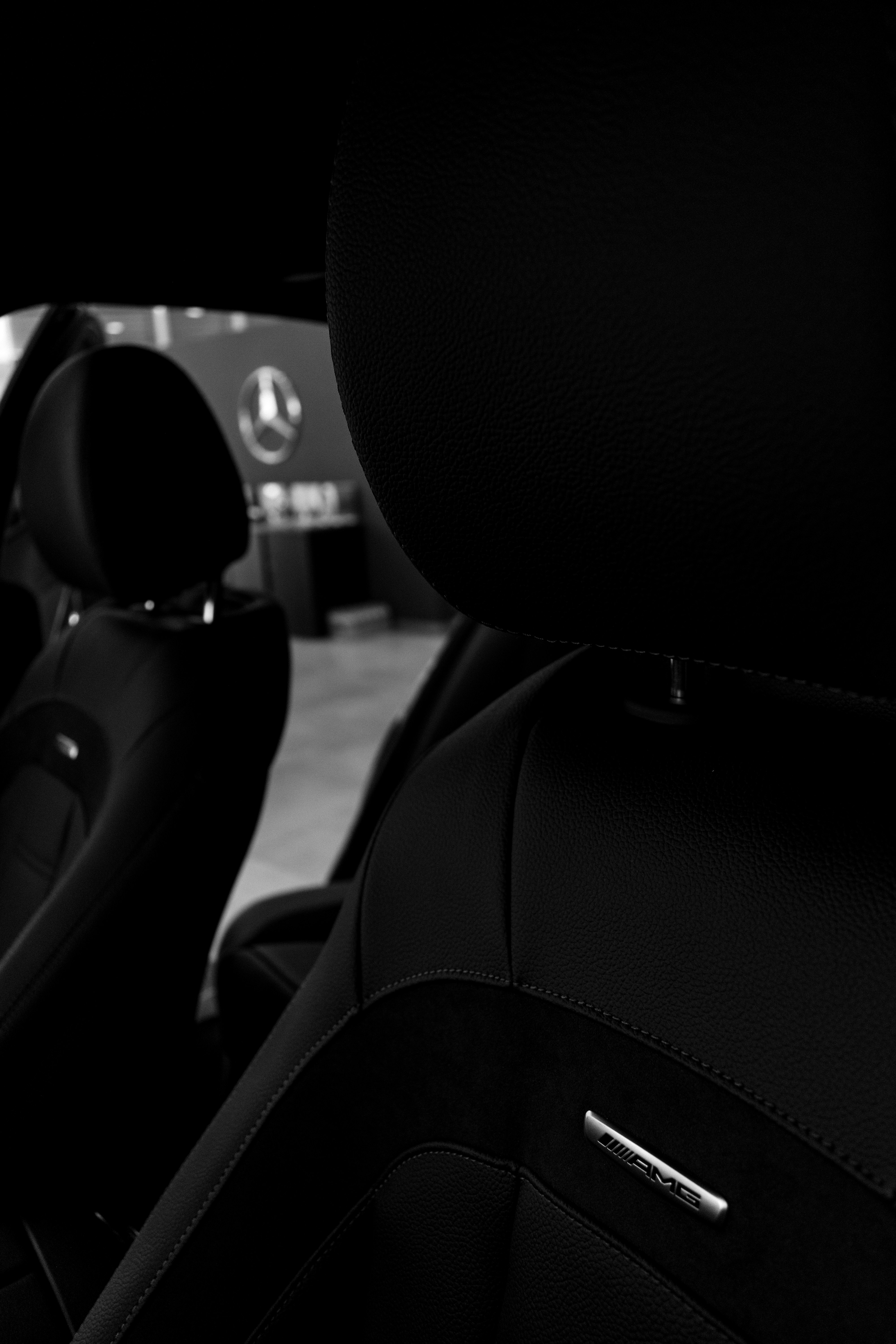 Close-up of a luxurious car seat with an AMG badge, showcasing premium materials and design elements in a sleek automotive interior.
