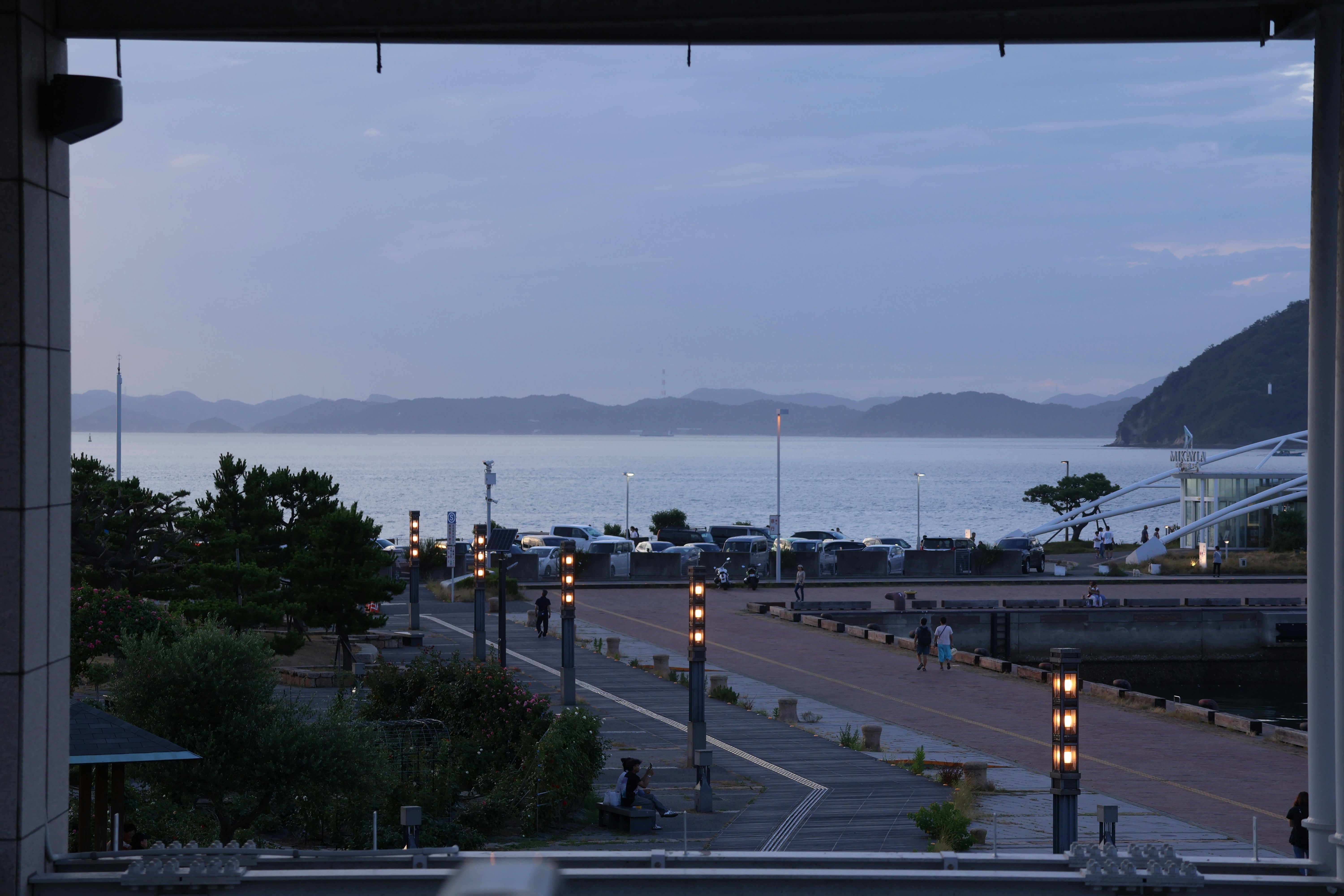 Coastal road with streetlights near the ocean at dusk