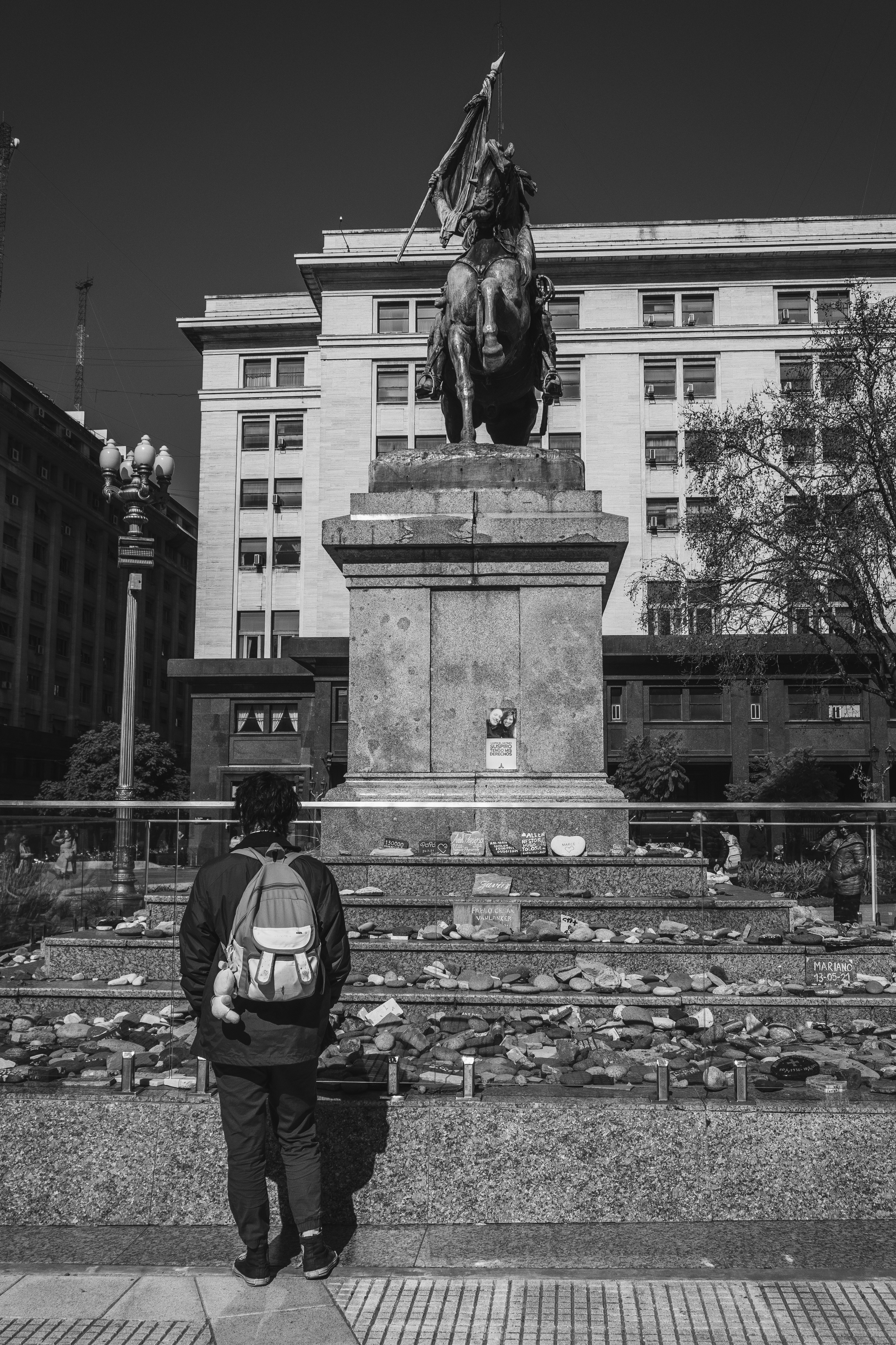 Tourists standing by the statue of Manoel Belgrano and the memorial for the victims of the pandemic (the stones placed at the steps of the statue base, each one in memory of a person who didn't have the opportunity to survive it).