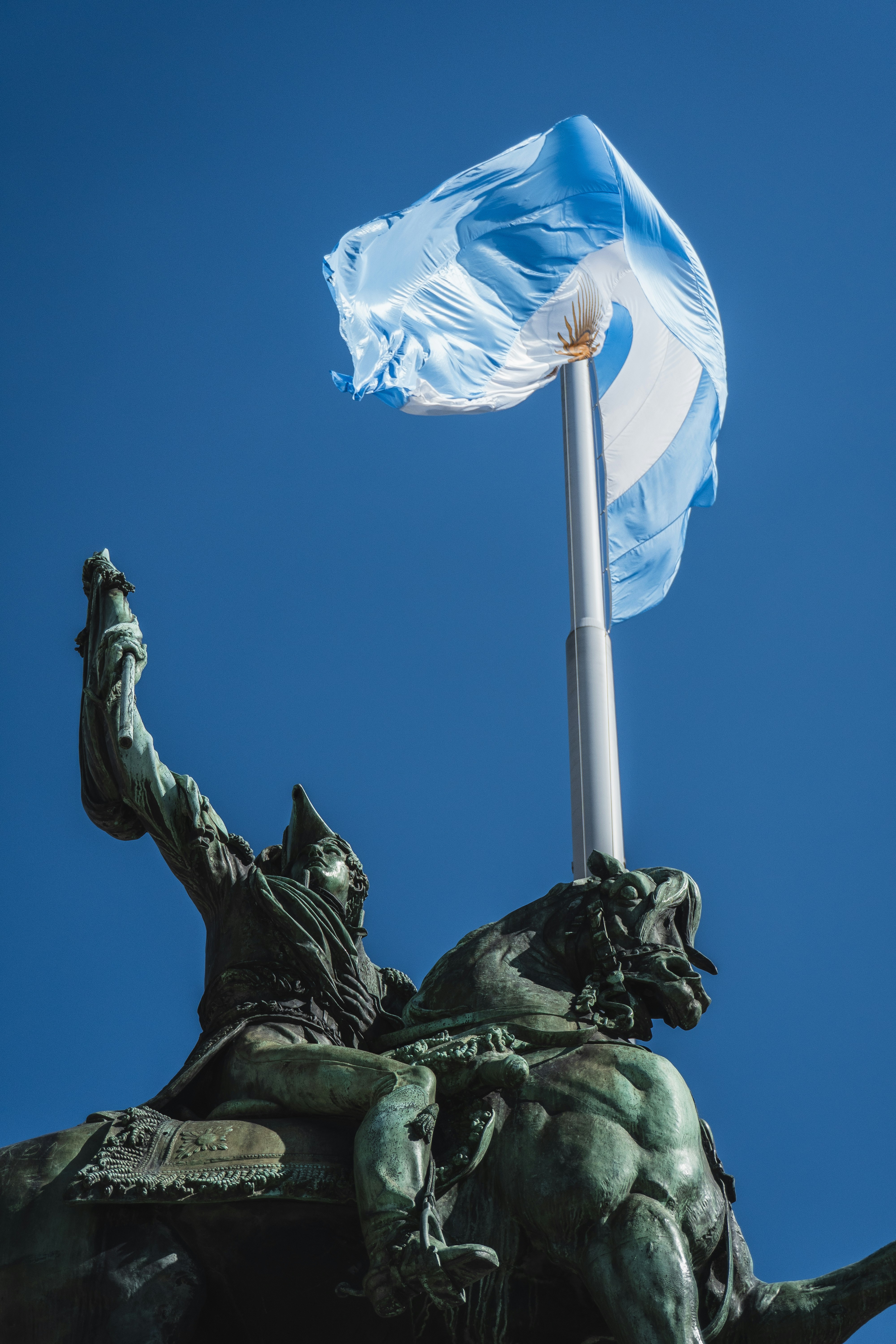 Cerulean Flag Unfurls Behind a Bronze Monument