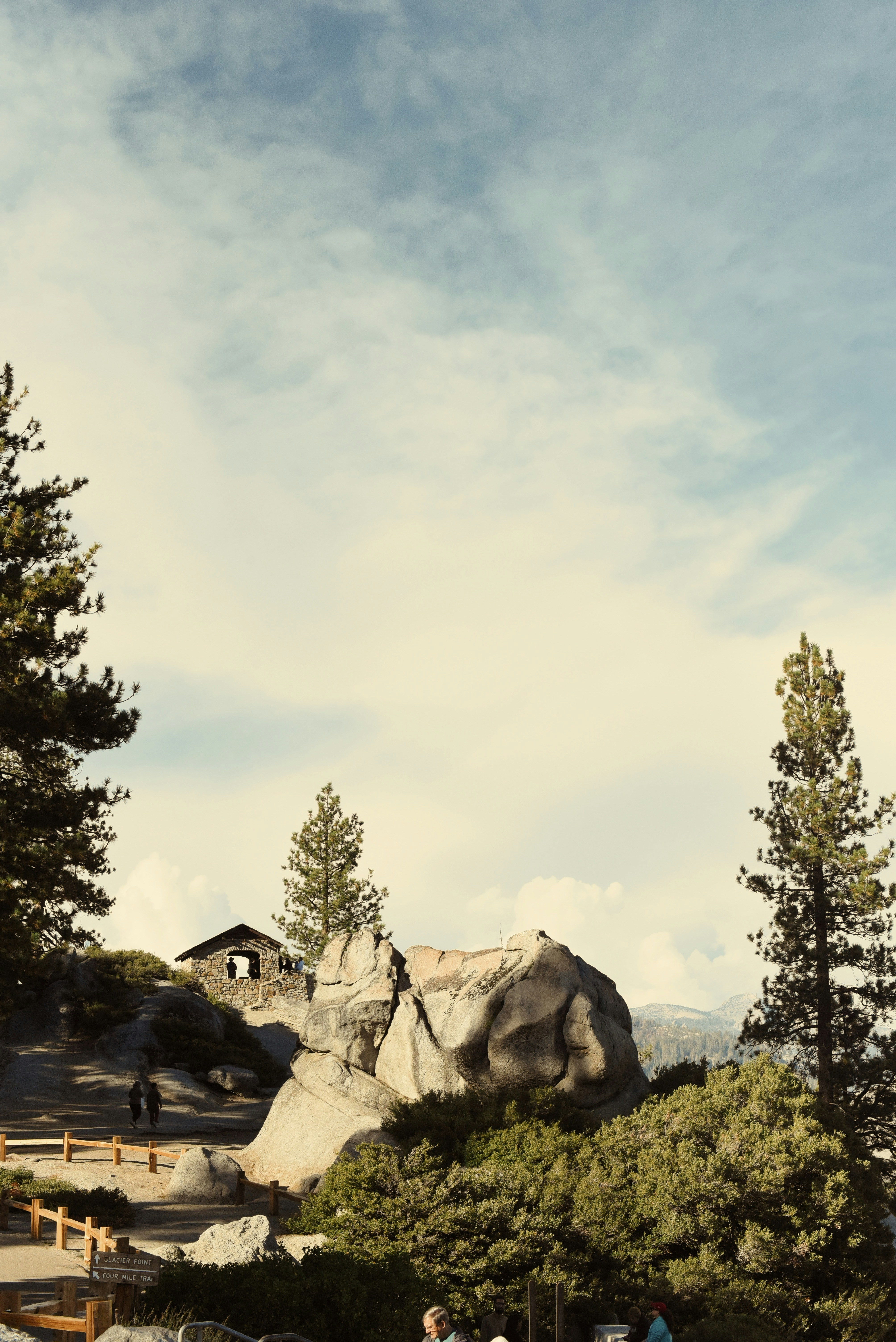 Lush greenery and rugged boulders frame a serene outdoor scene, with a quaint cabin nestled among the trees. The sky stretches above, hinting at a tranquil day outdoors.