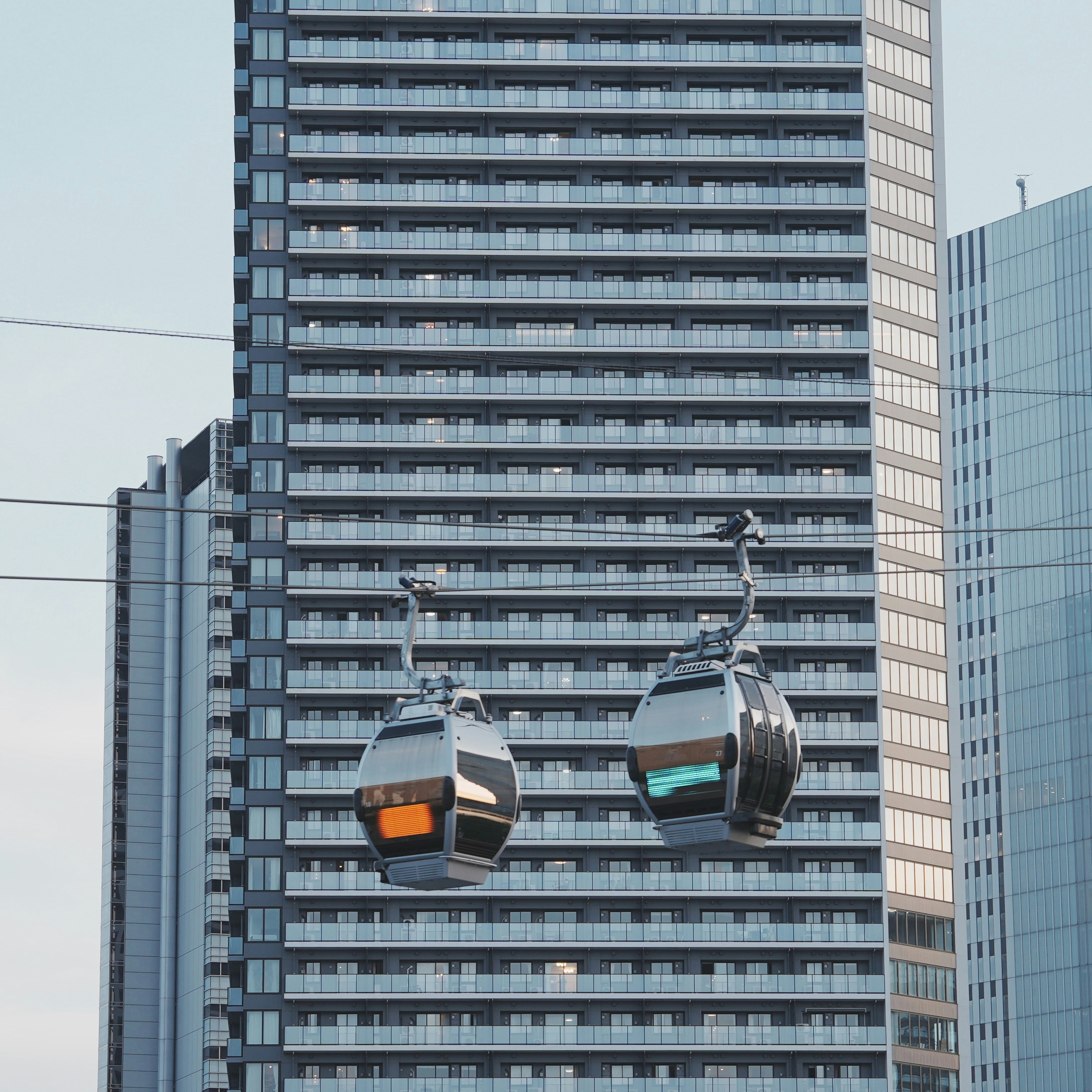 Cable car in front of the building. | Two cable cars ascend past modern high-rise buildings.