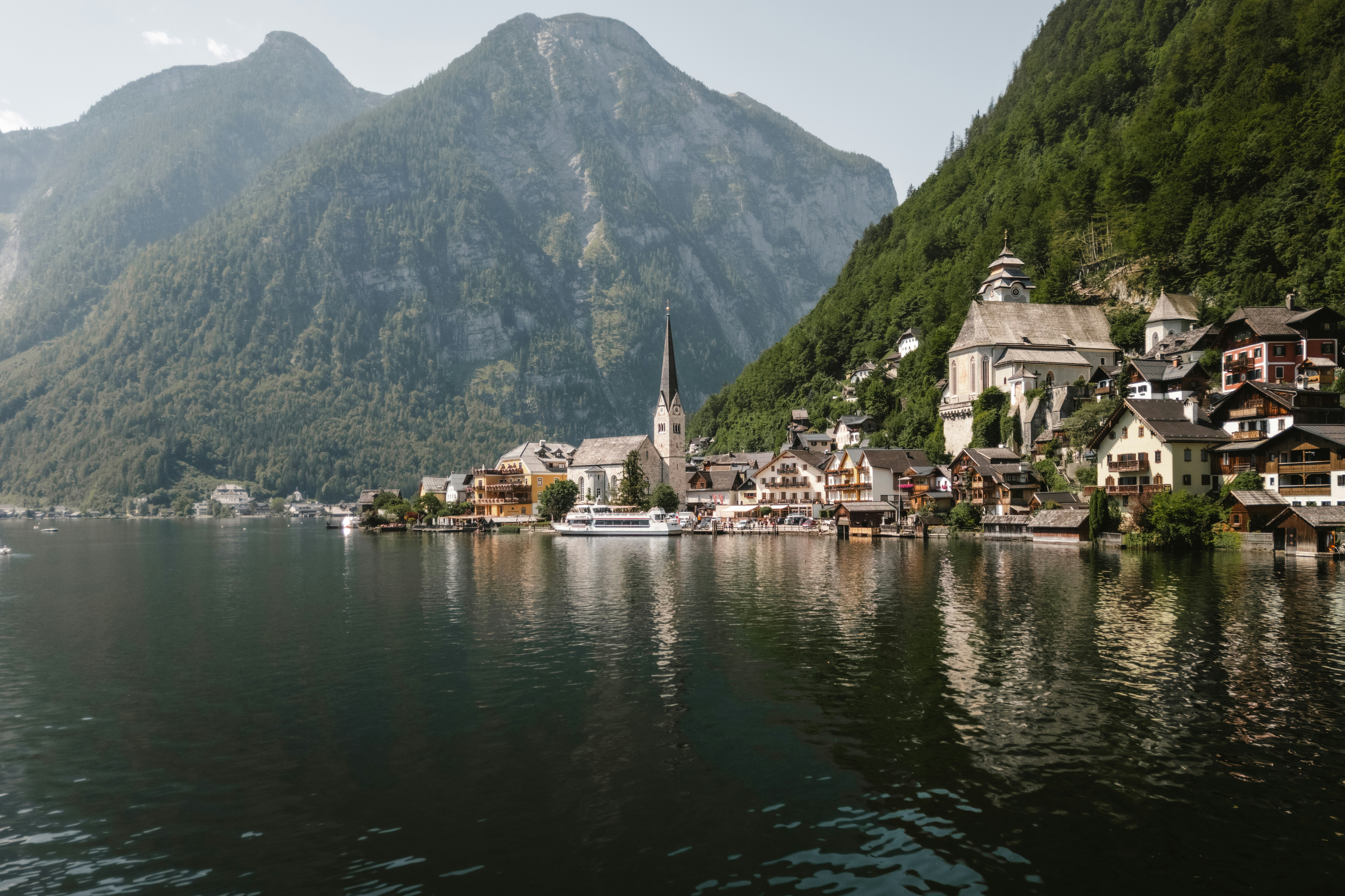 Tranquil lakeside village with mountain backdrop | Picturesque village nestled beside a calm lake and mountains.