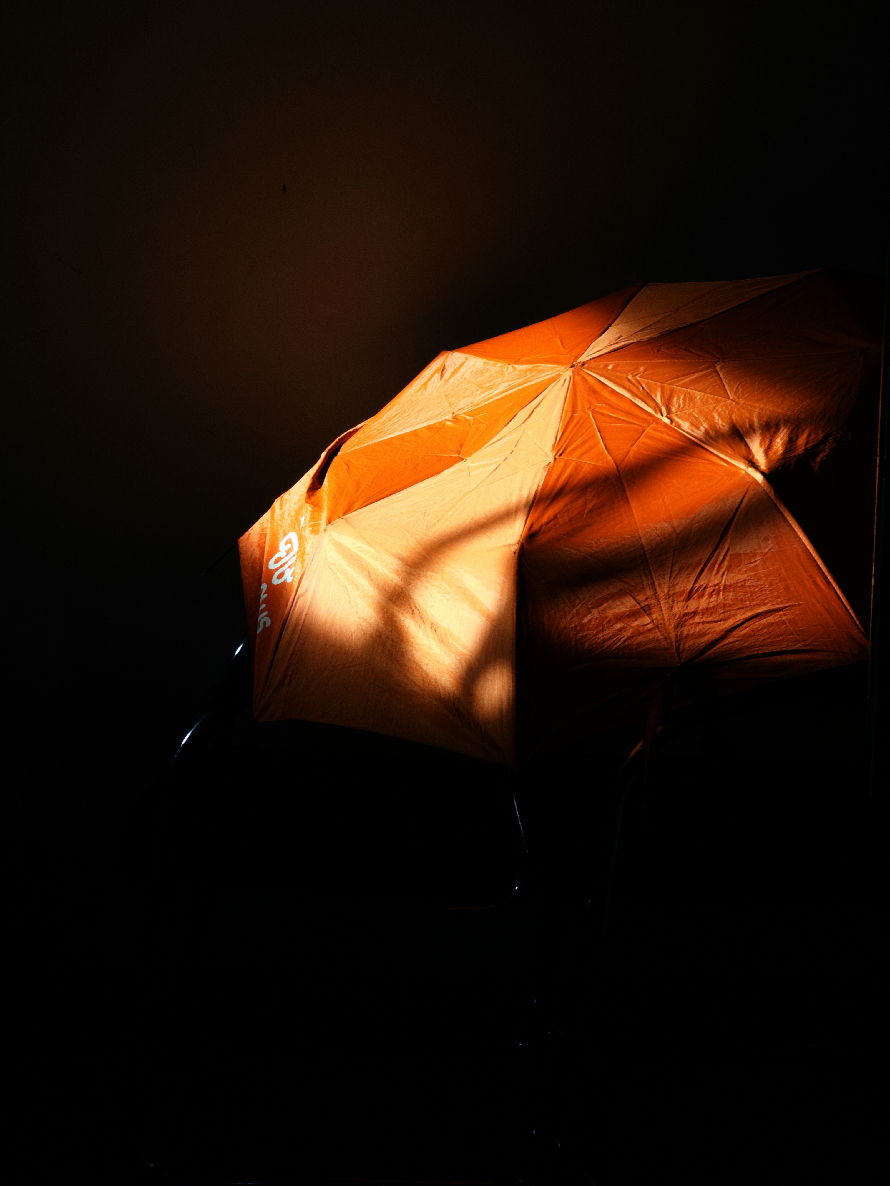 Orange umbrella illuminated by dramatic light