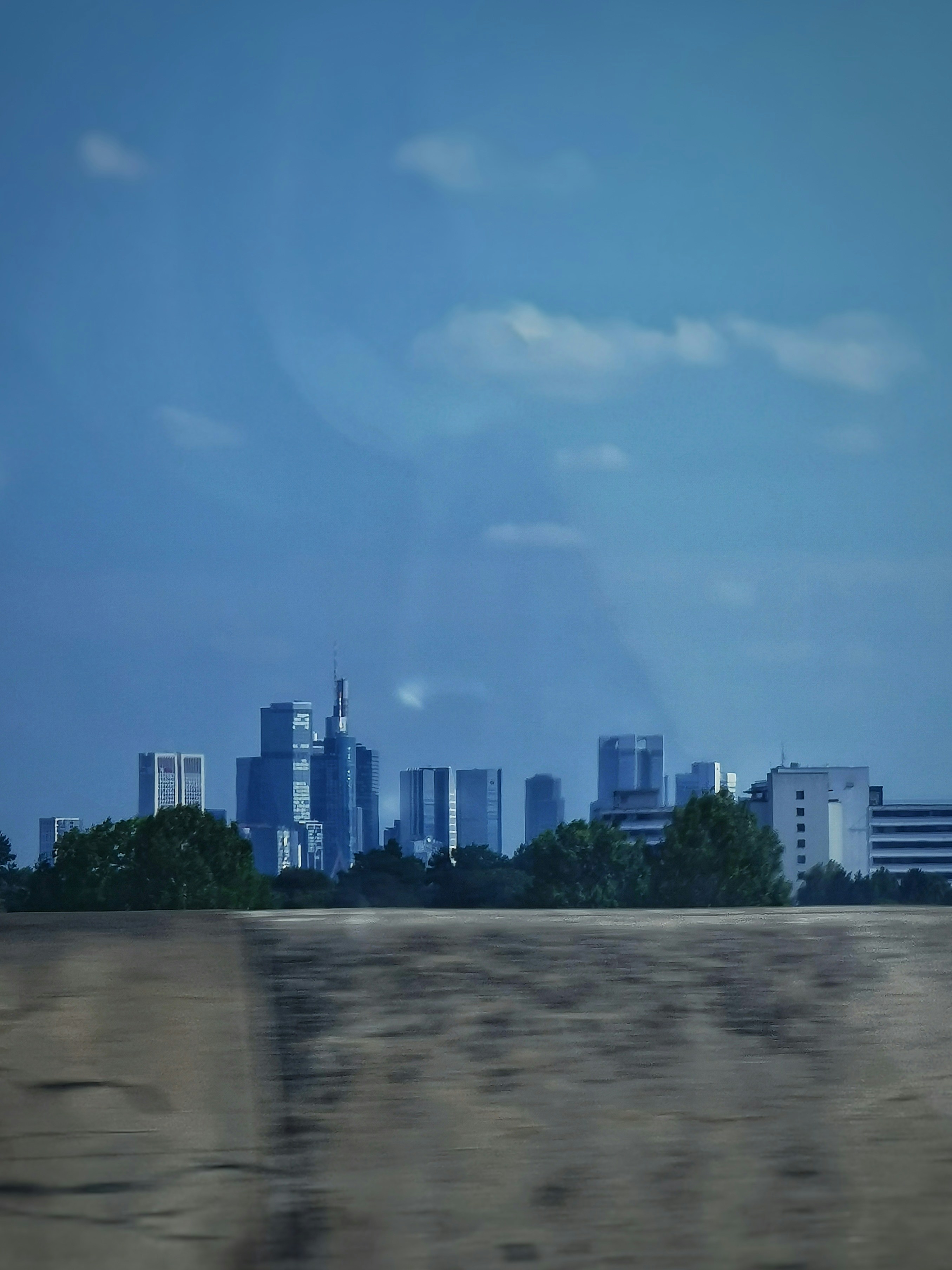 Modern city skyline with trees and blue sky.