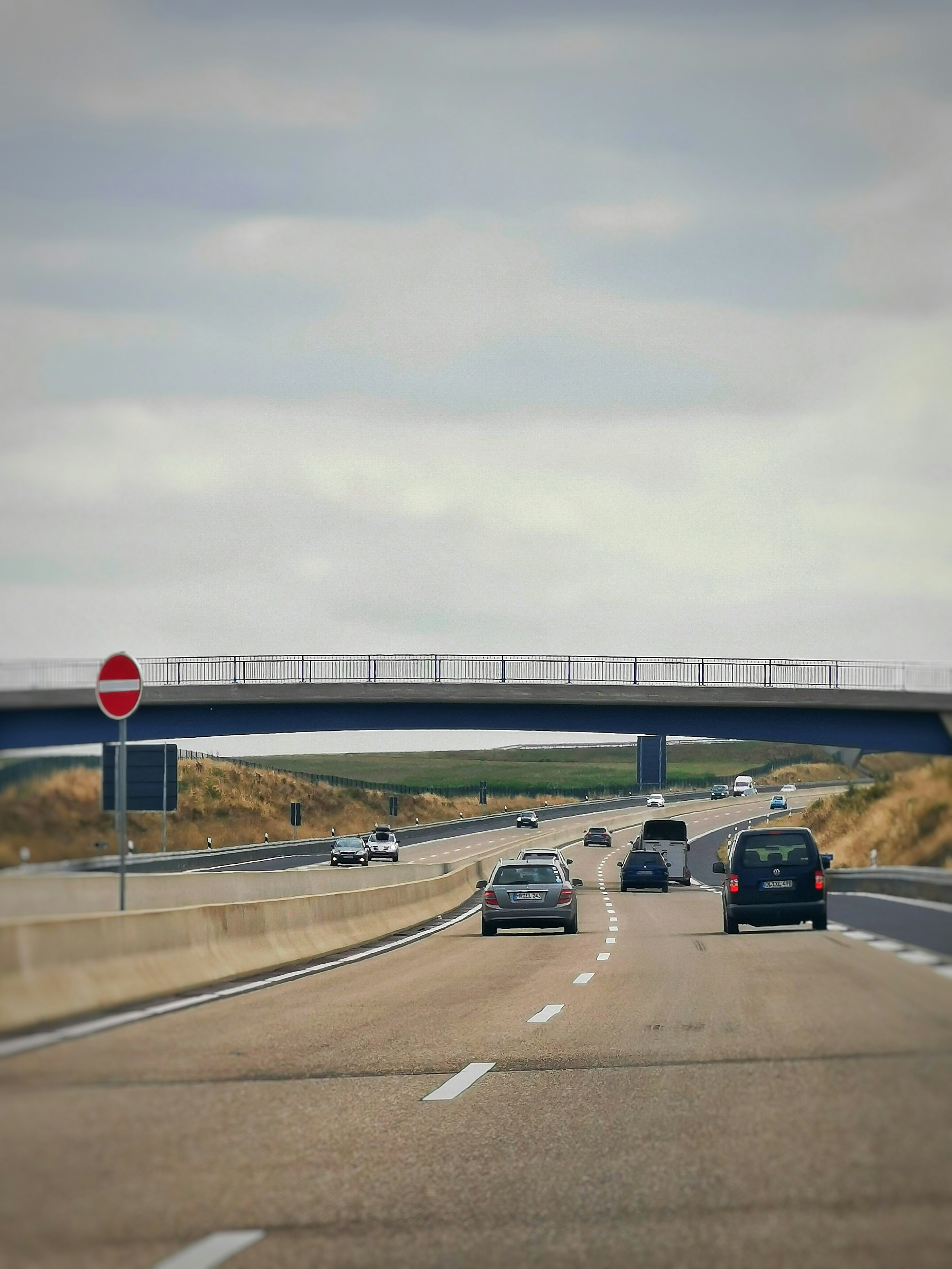 Cars driving on a highway under a bridge.