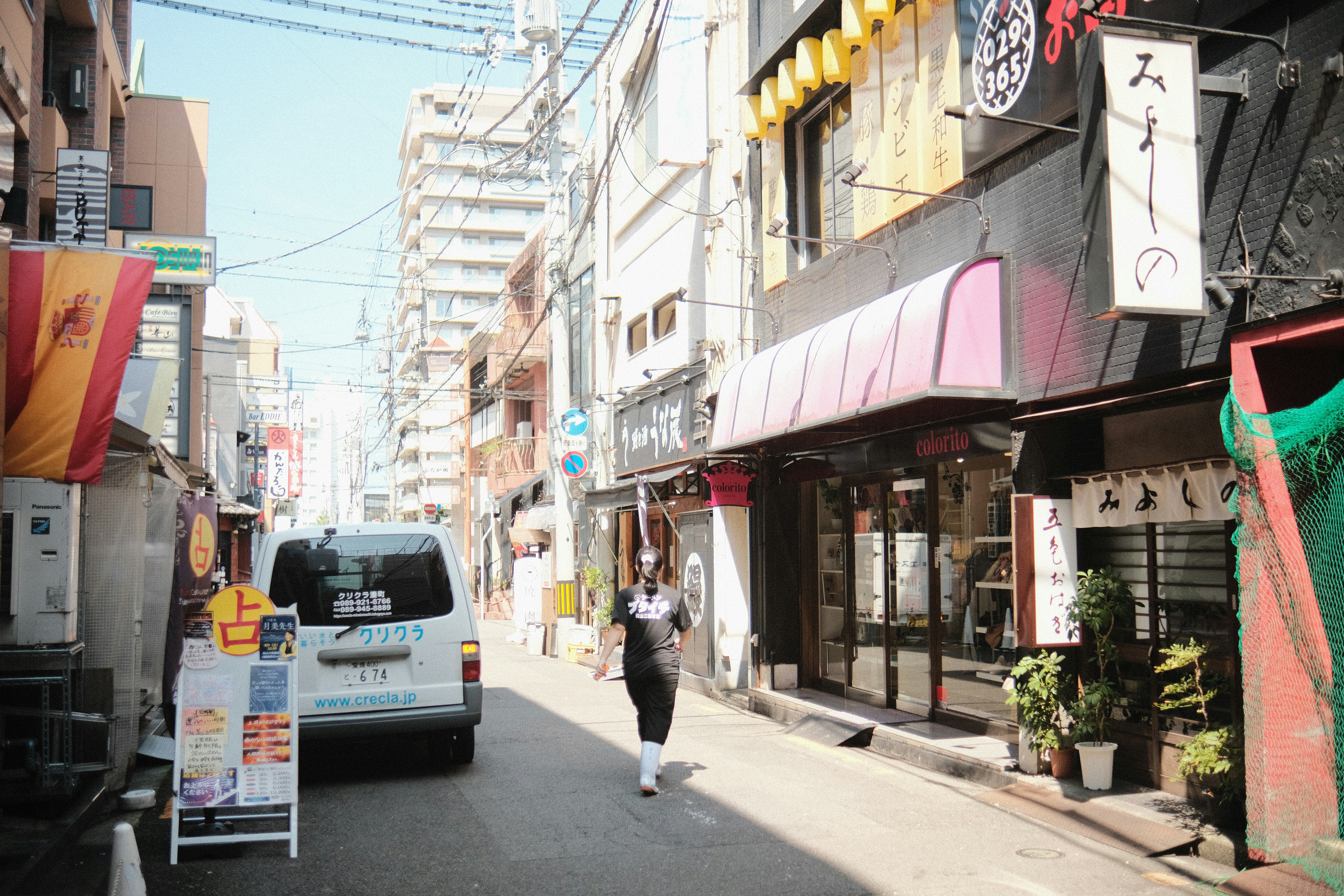 Woman walking down a narrow street with buildings.