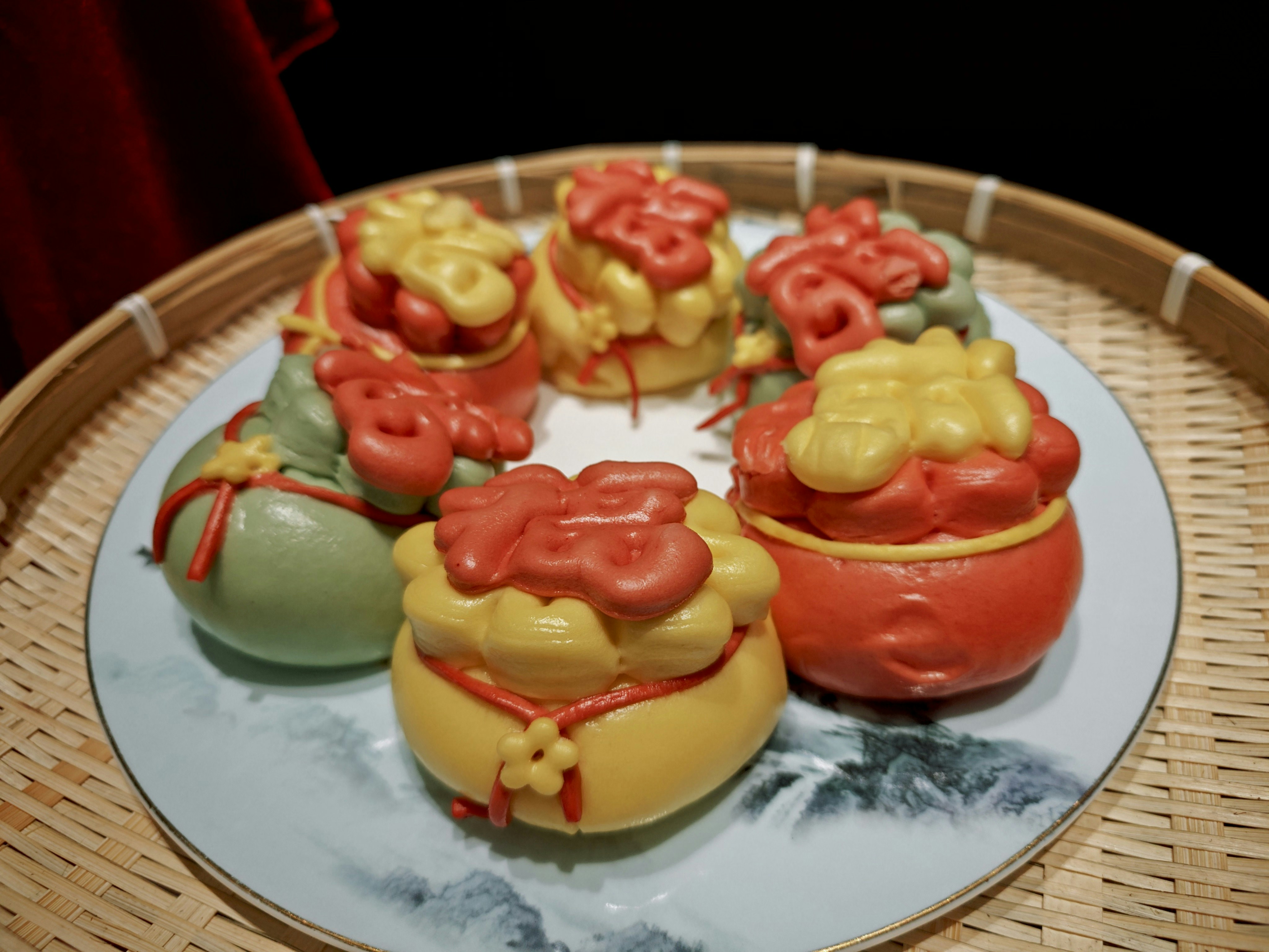 Colorful traditional pastries arranged in a circular pattern on a decorative plate, showcasing intricate designs and vibrant hues.