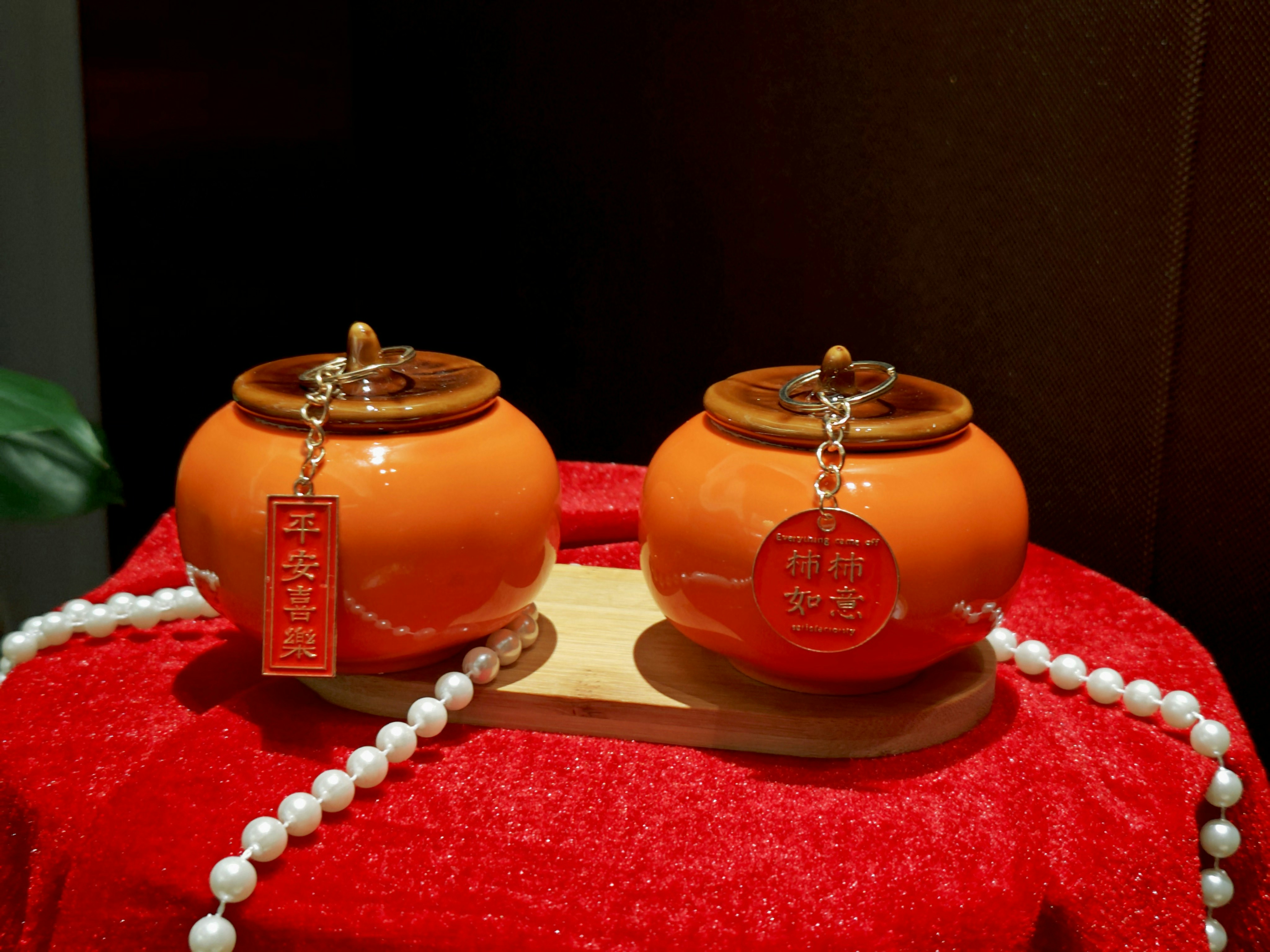 Two orange ceramic jars with red tags.