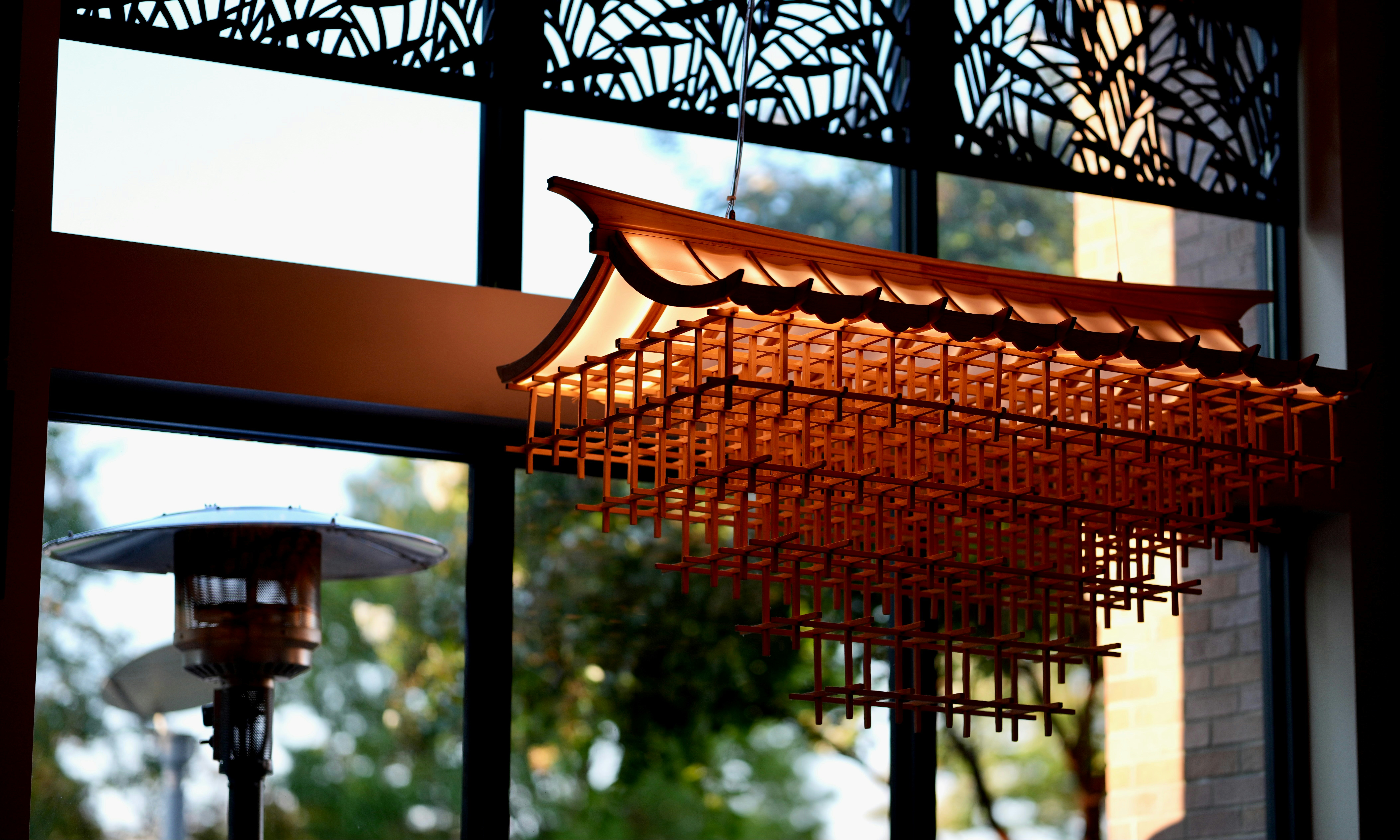 Decorative wooden chandelier hangs near window