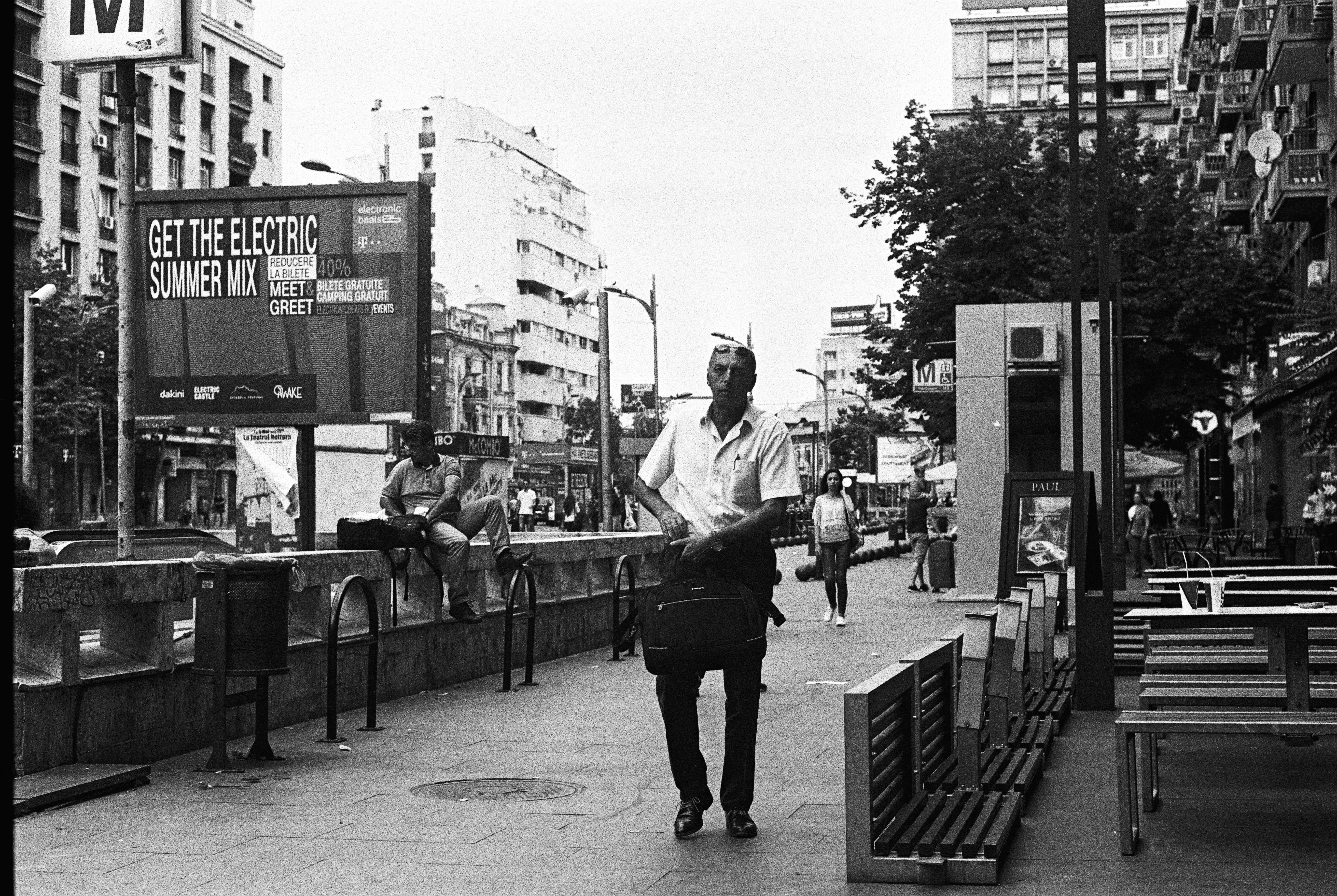 Man walks on a city street with buildings behind him buildings
