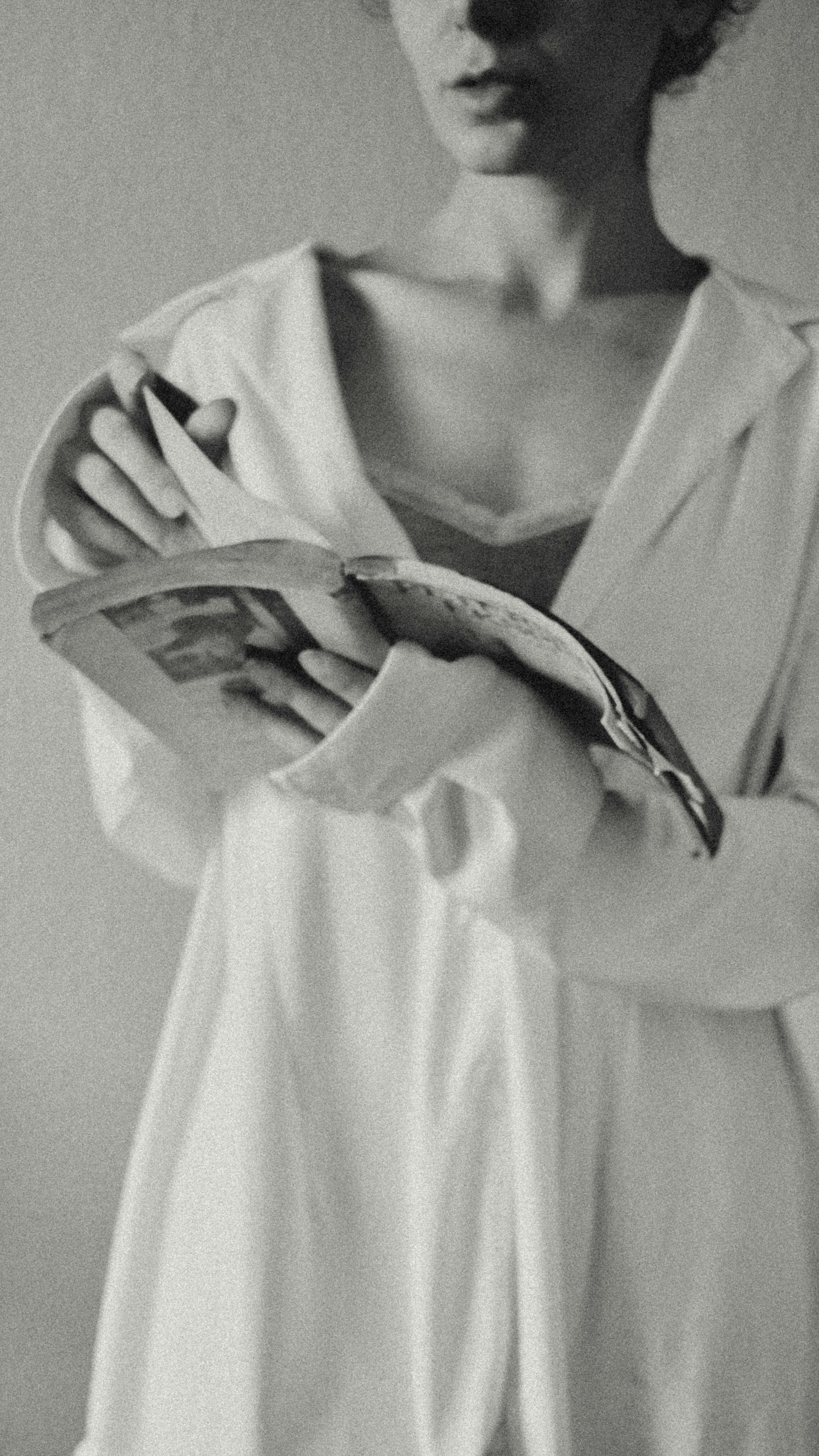 The woman reading a book. | Woman in white shirt reading an open book.