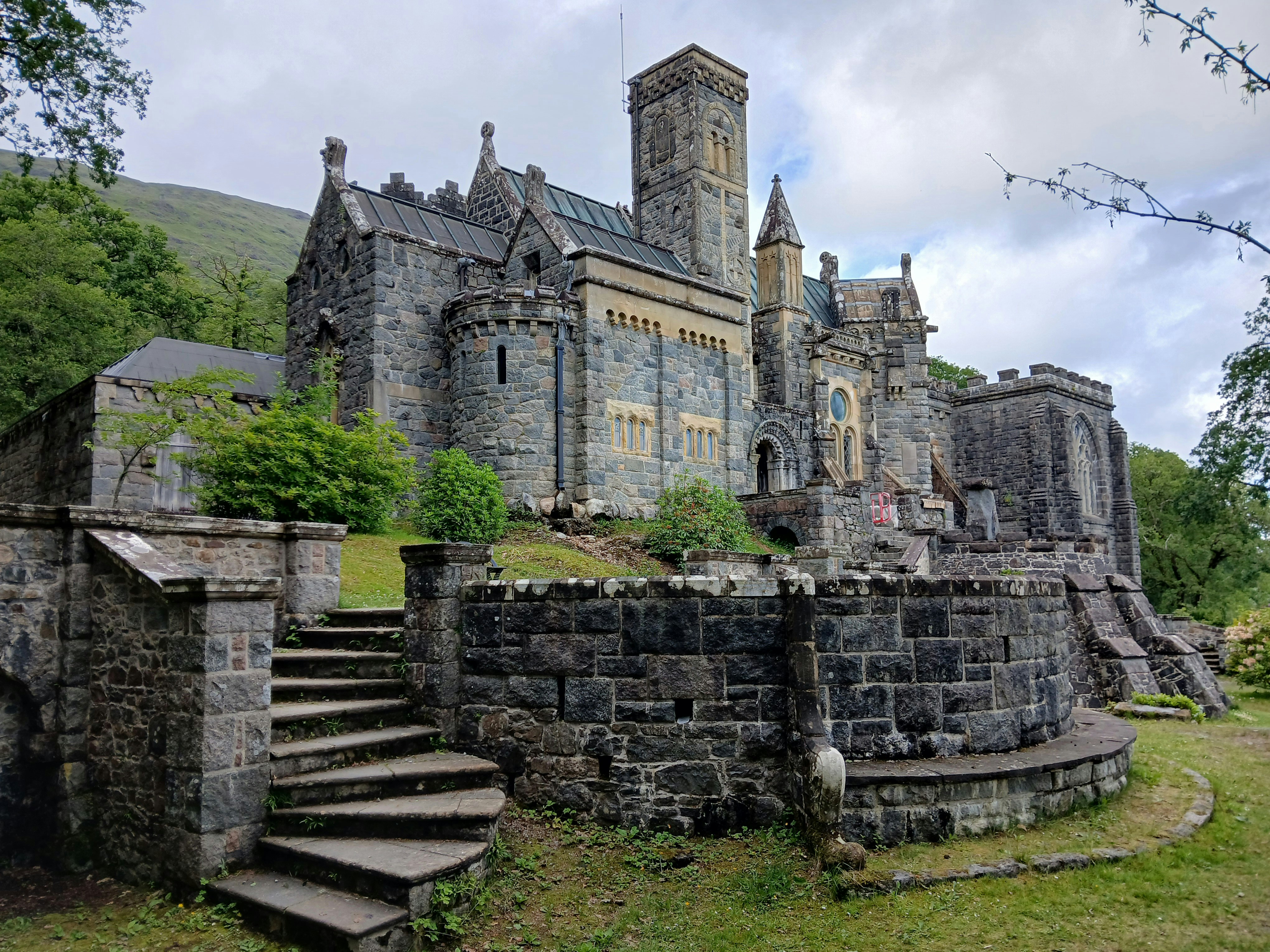 Stone castle with tower and stairs in greenery