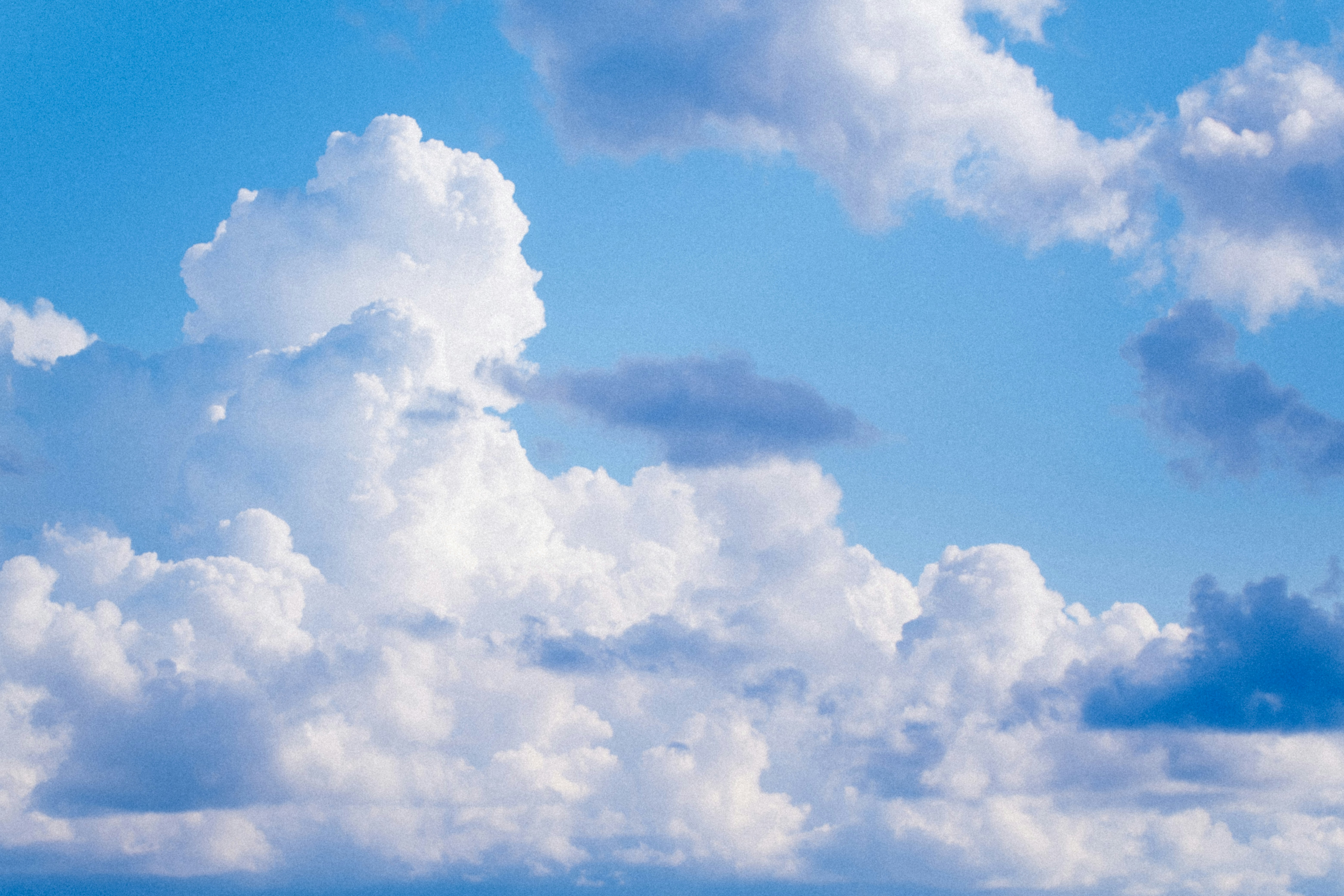 Fluffy white clouds against a bright blue sky