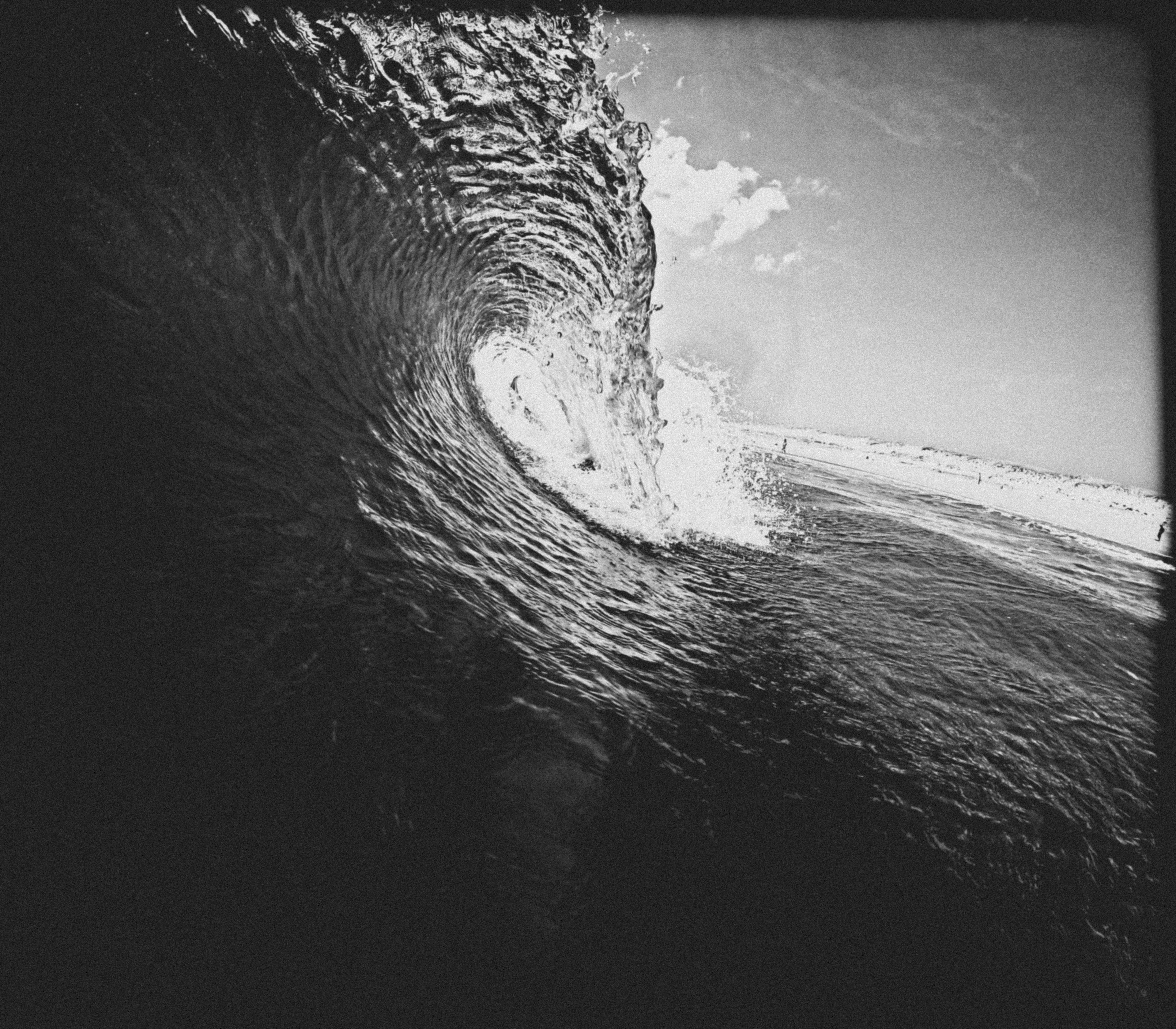 Dynamic view from within a breaking wave, showcasing the swirling water and bright sky above. The image captures the essence of surfing culture.