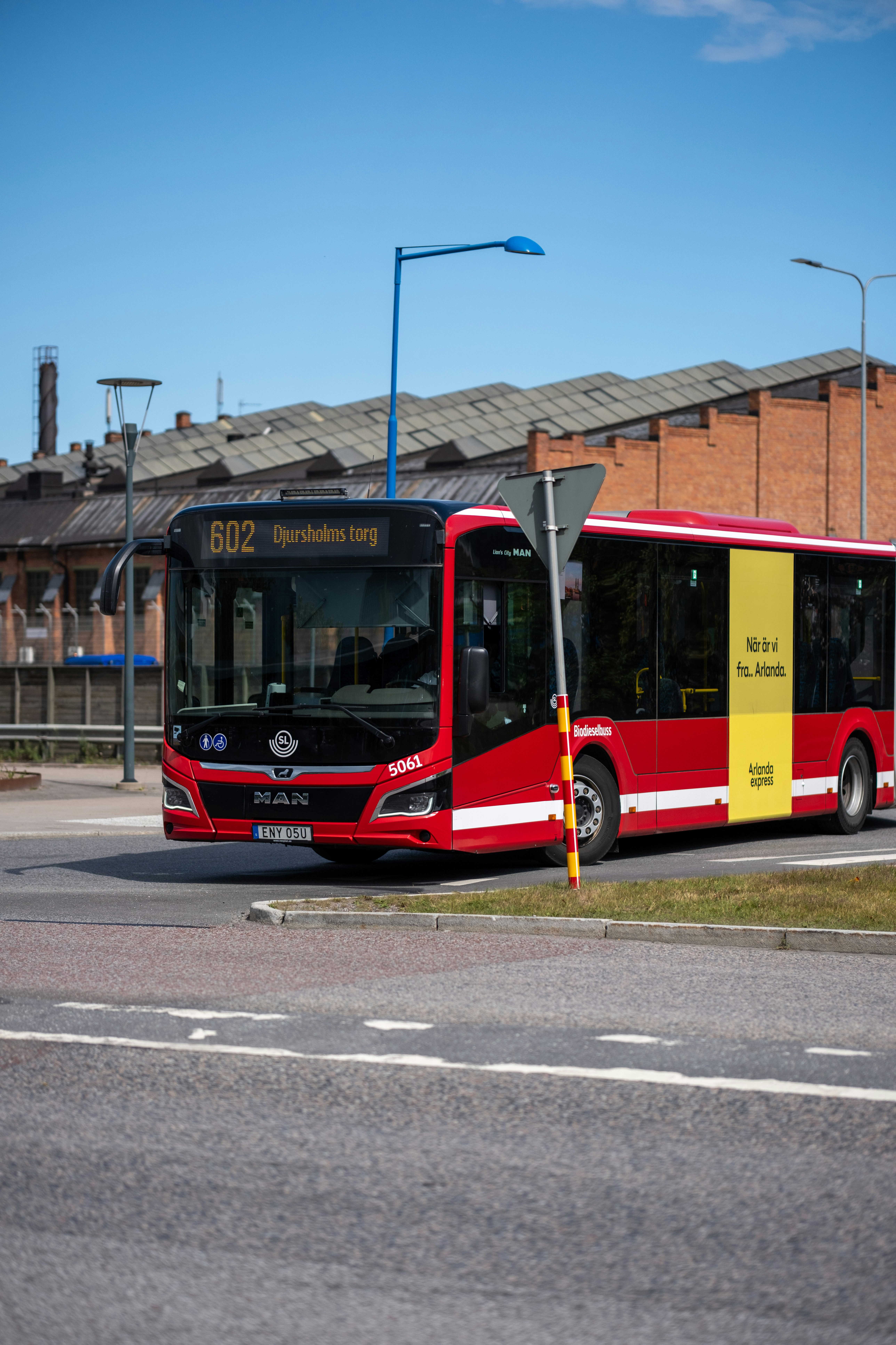 Red city bus driving on a sunny day.