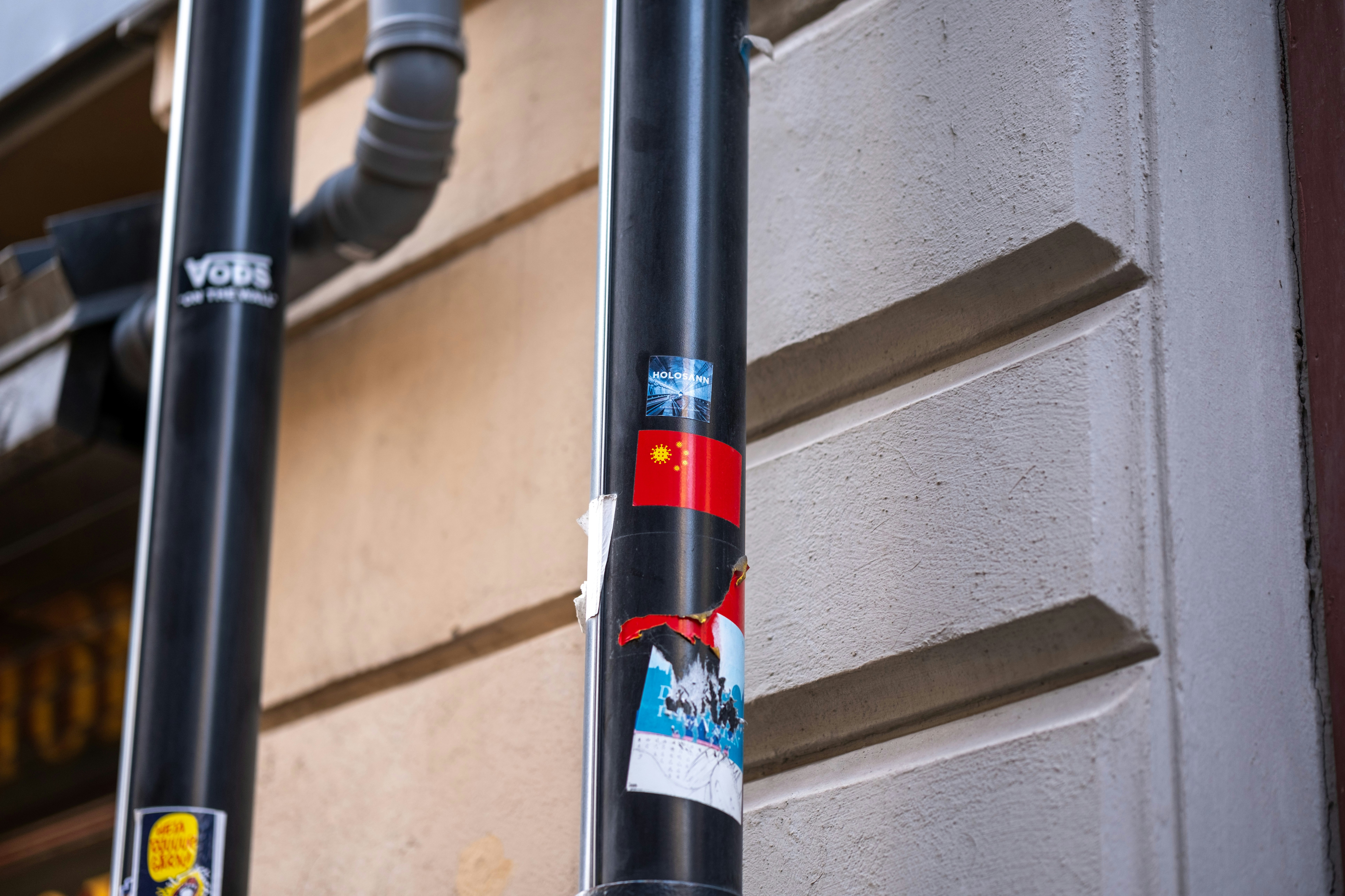 Stenciled Red Flag on Urban Pipe: A Routine Corner with Stickered Poles
